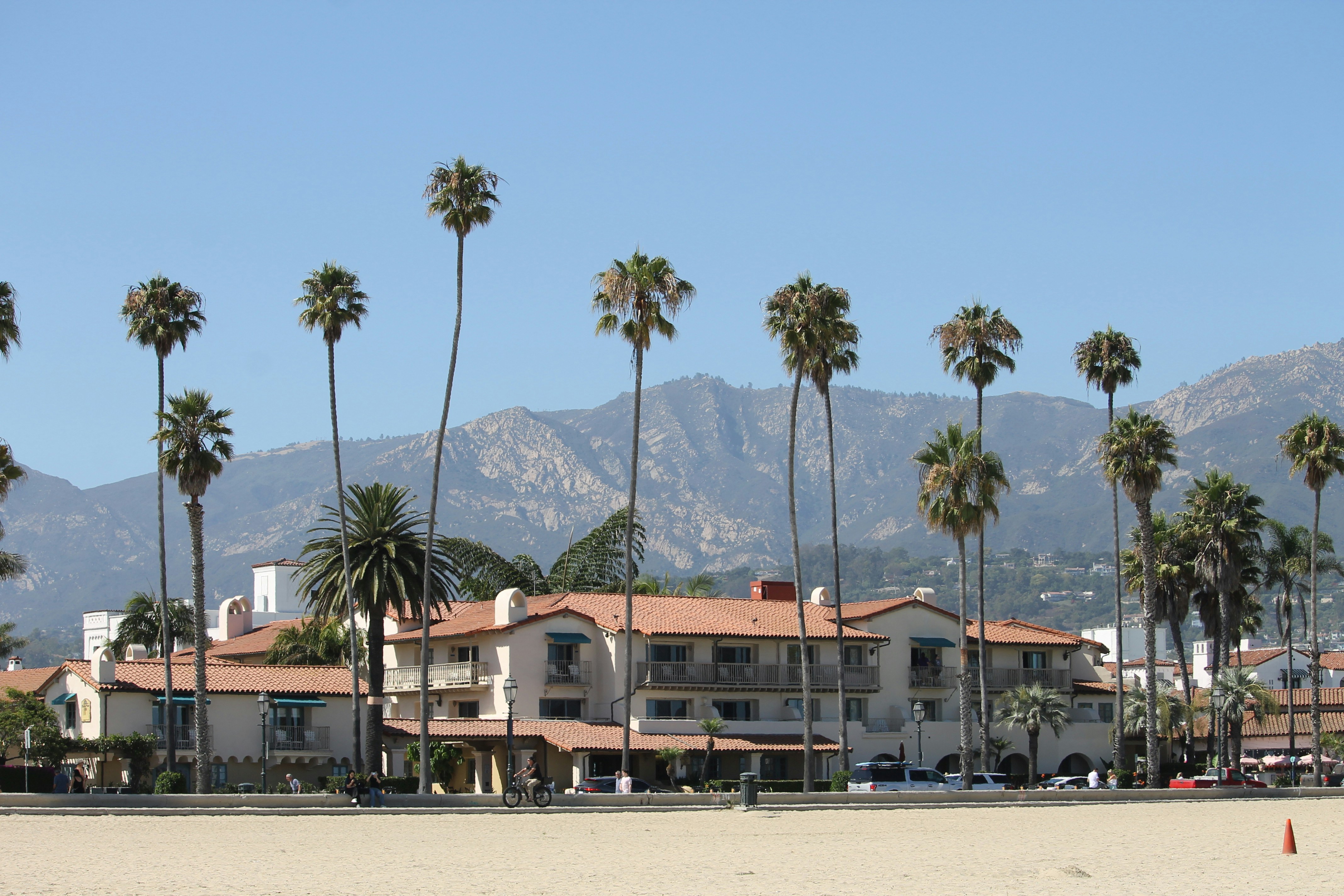 Building with palm trees in front of mountains.