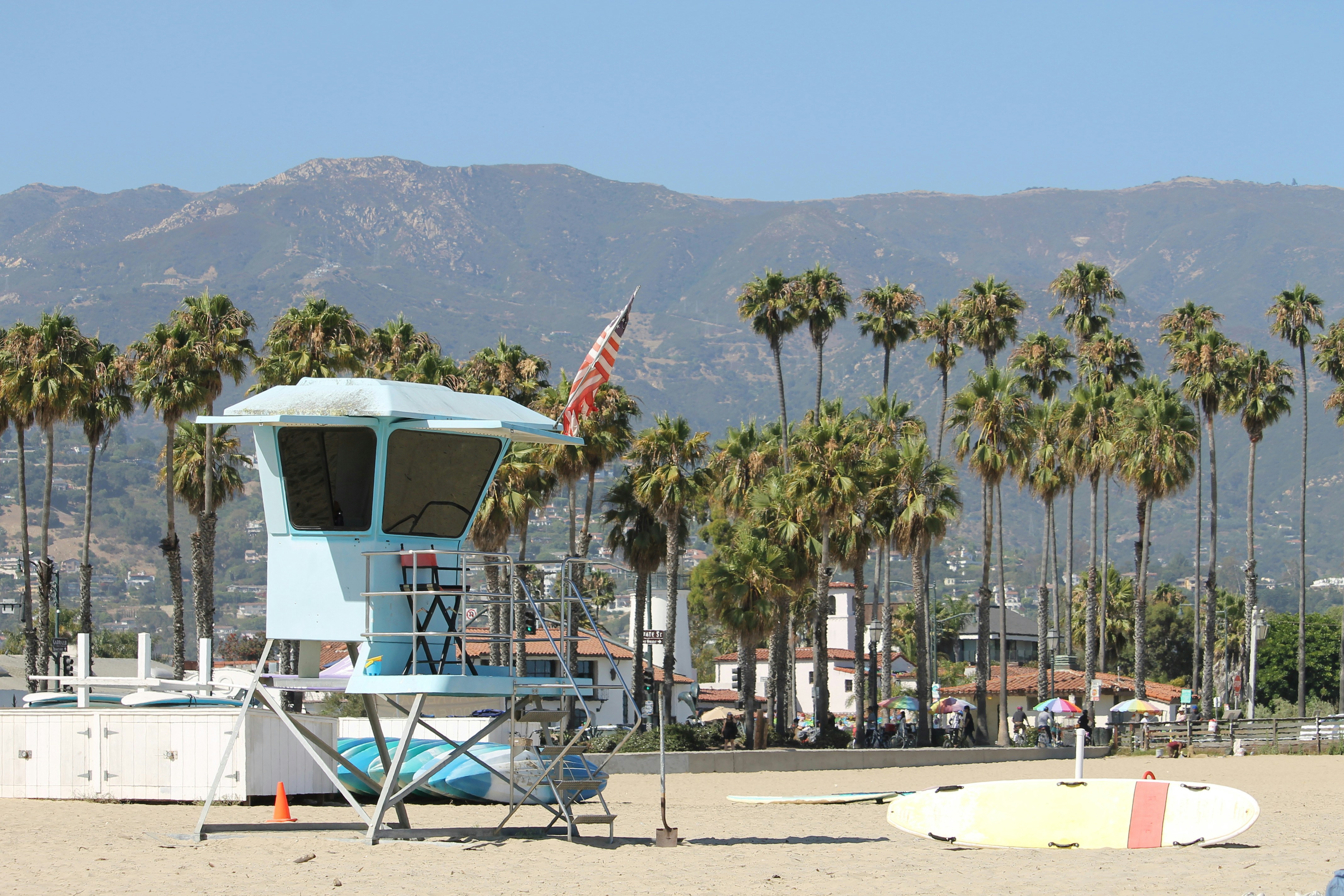 Light blue lifeguard tower on a sandy beach with palm trees.