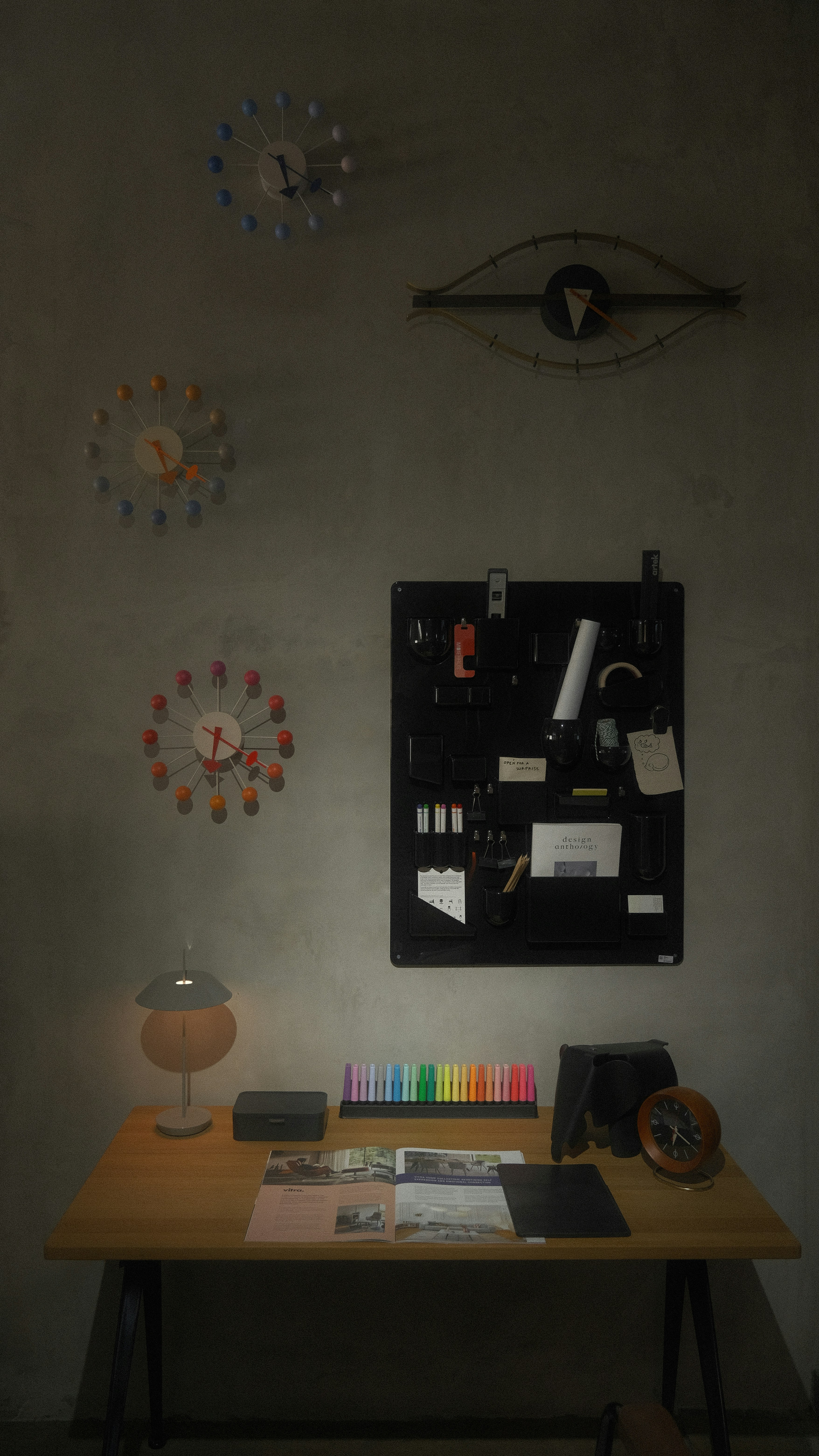 Desk with colorful markers and retro clocks on wall