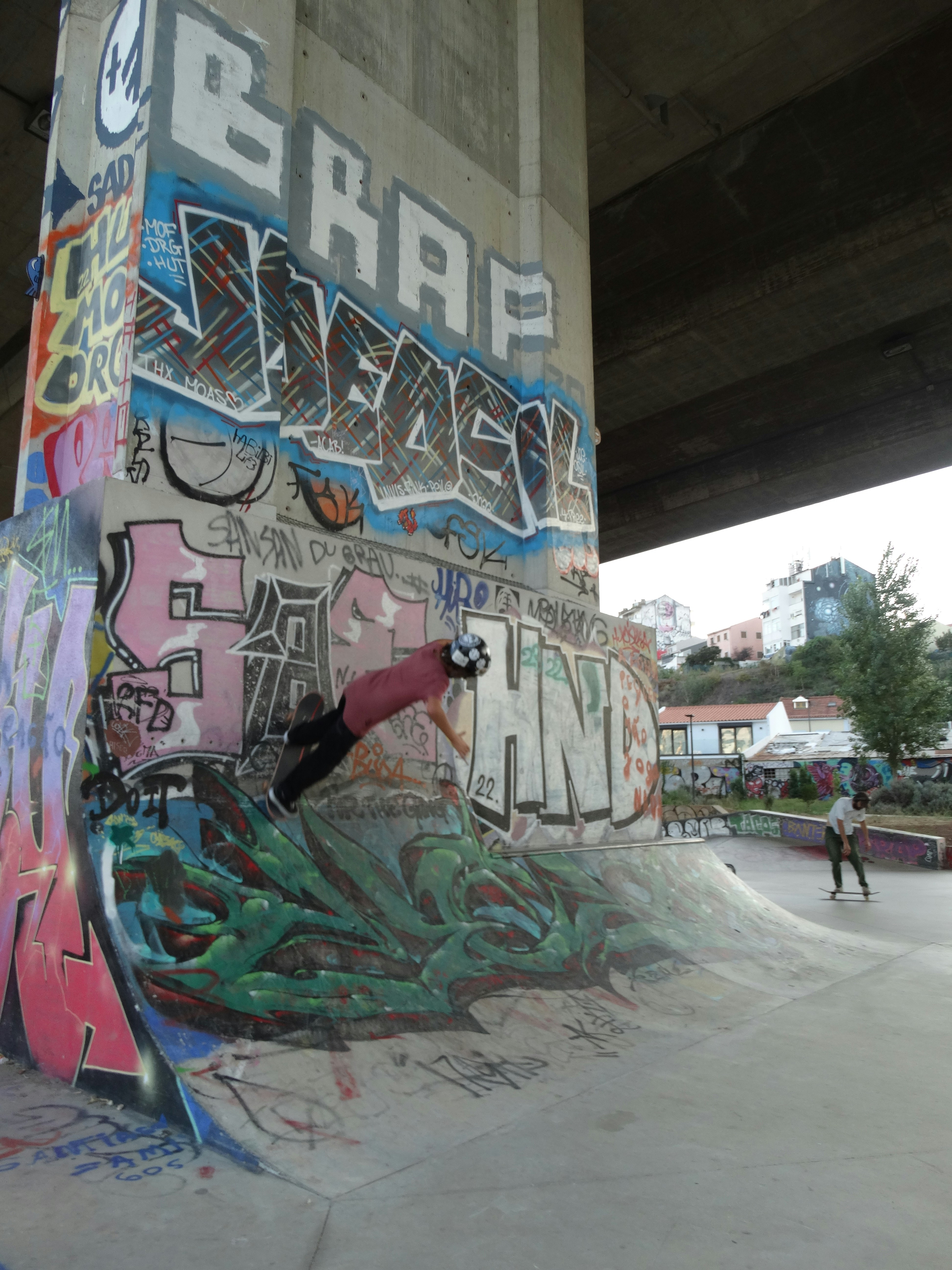 Na parede | Skateboarder performs trick under graffiti-covered bridge