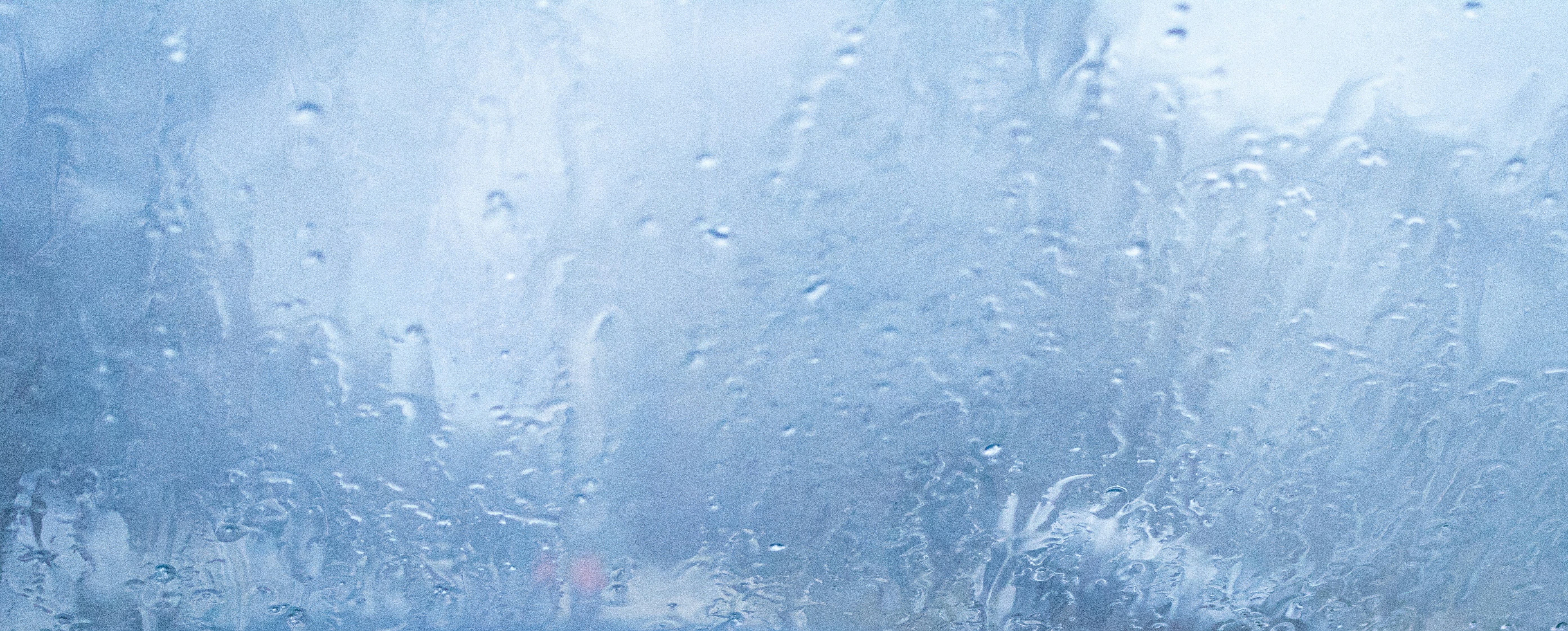 A glass with water droplets on it | Raindrops on a window with blurry background