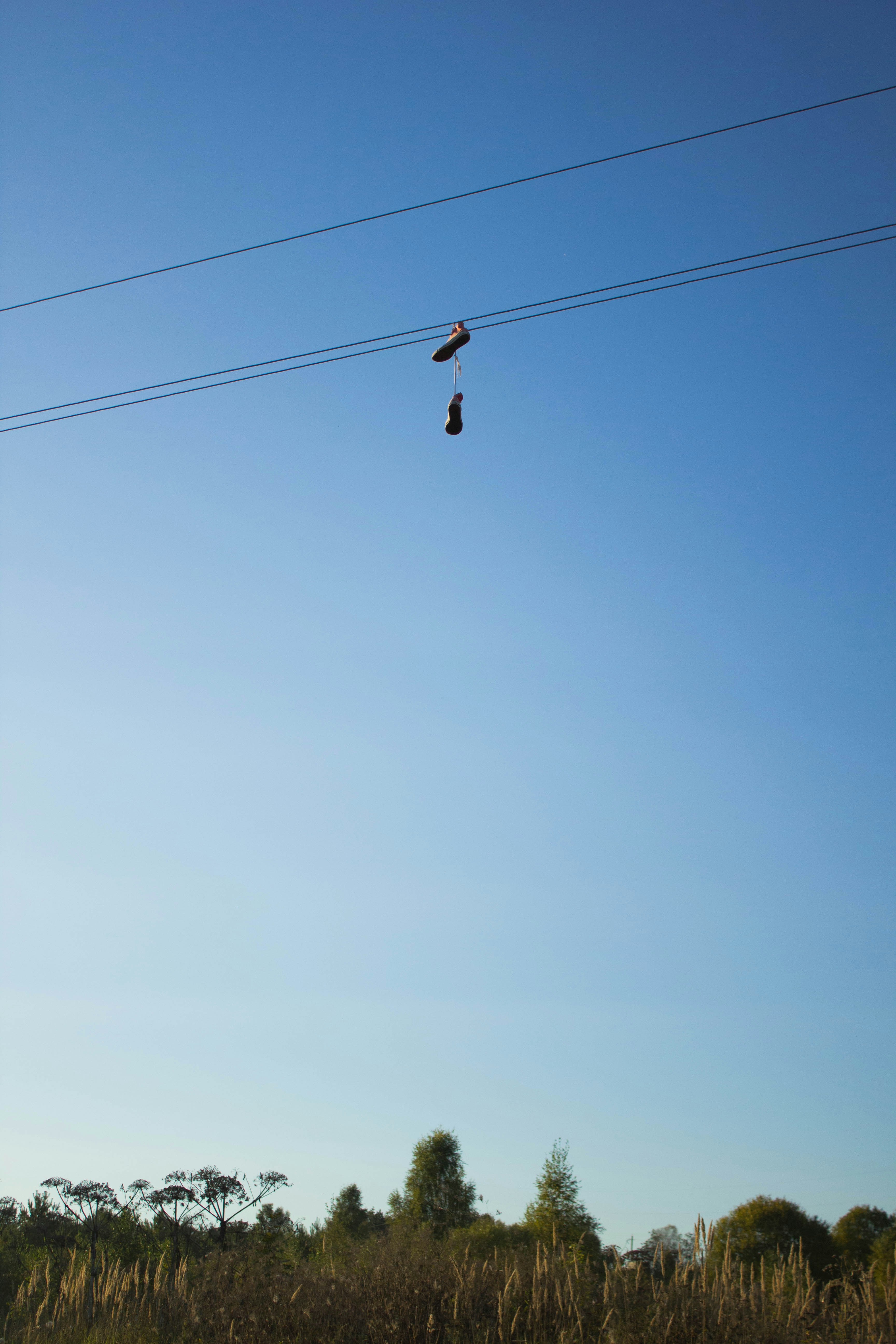 Shoes hanging on power line against clear blue sky