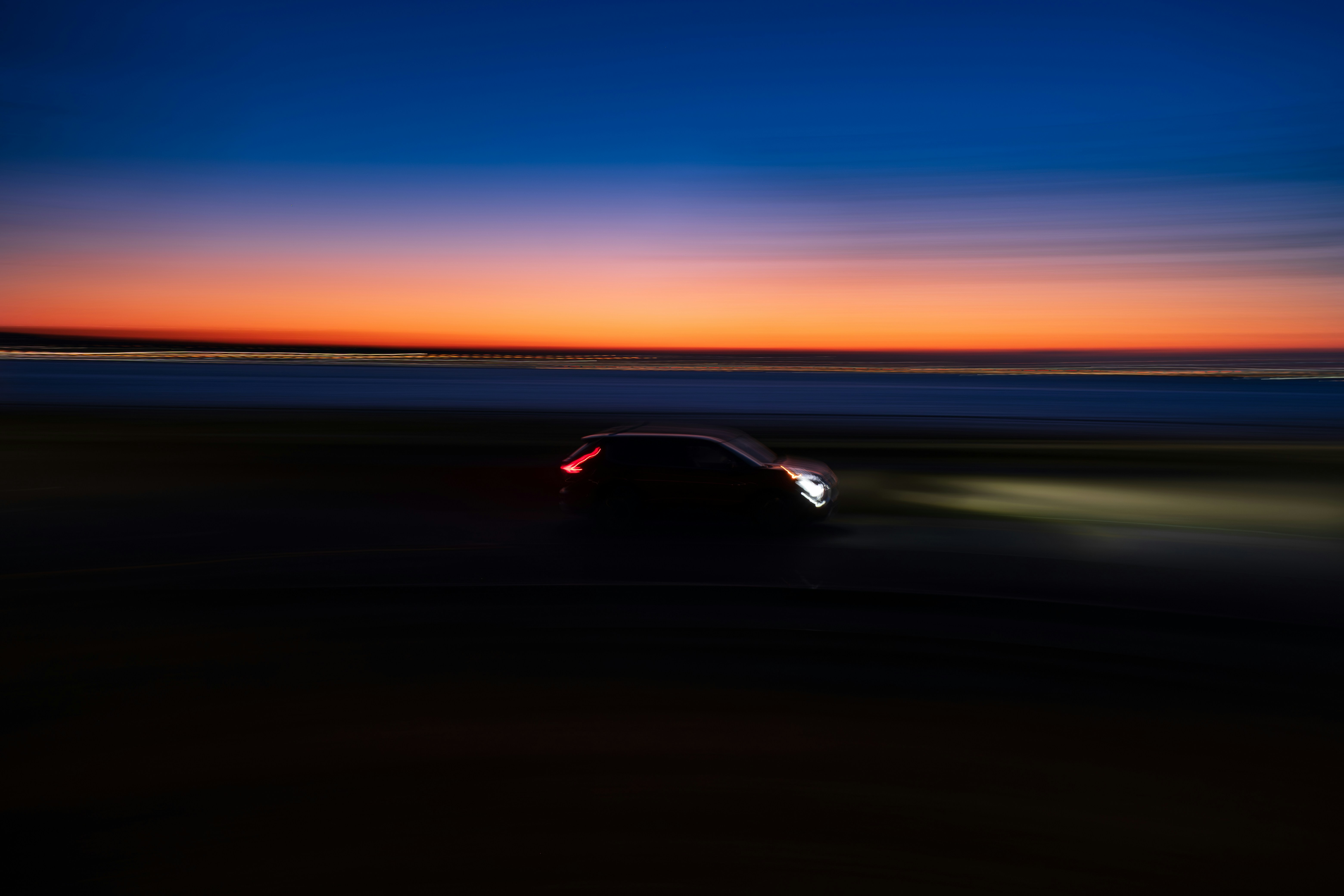 speeding car on highway at night, sunset blue hour background.