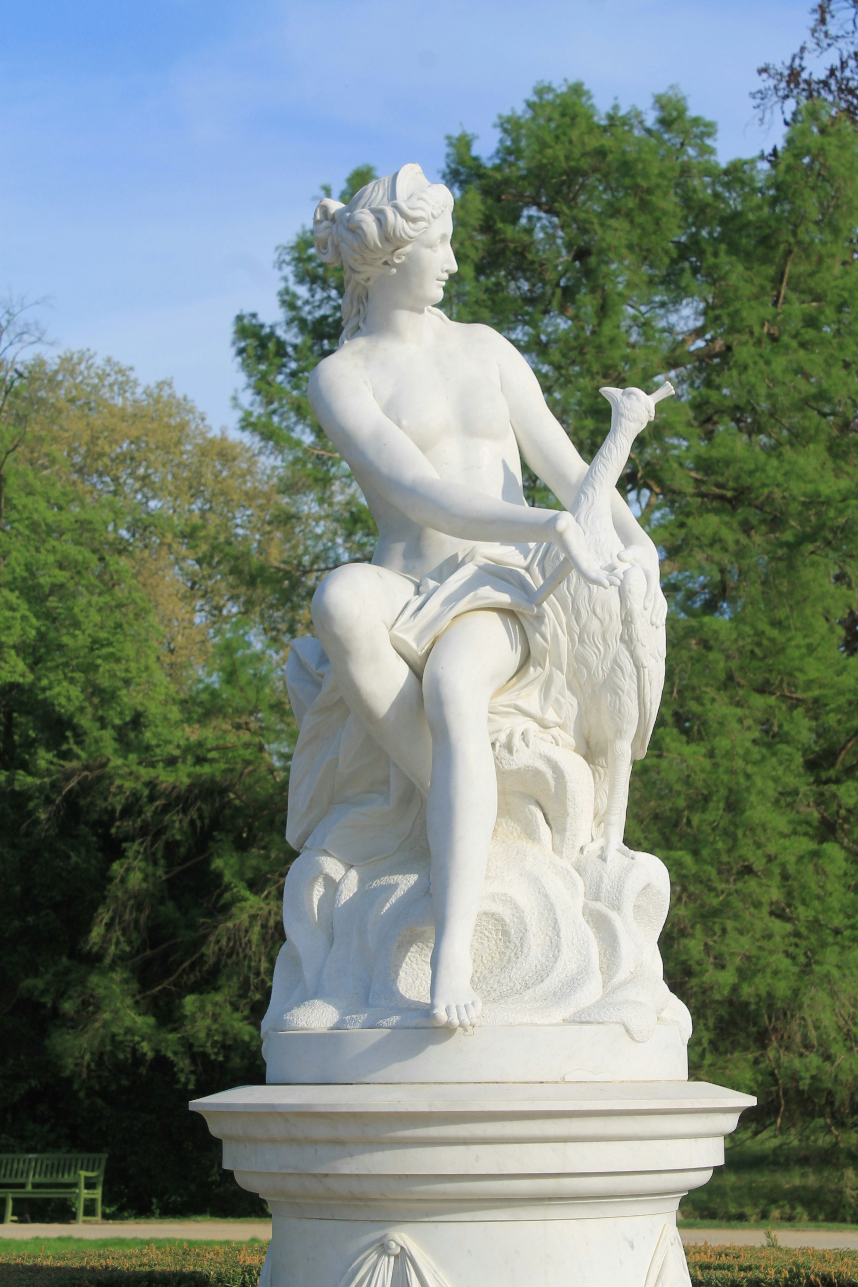 White marble statue of apollo with swan in park