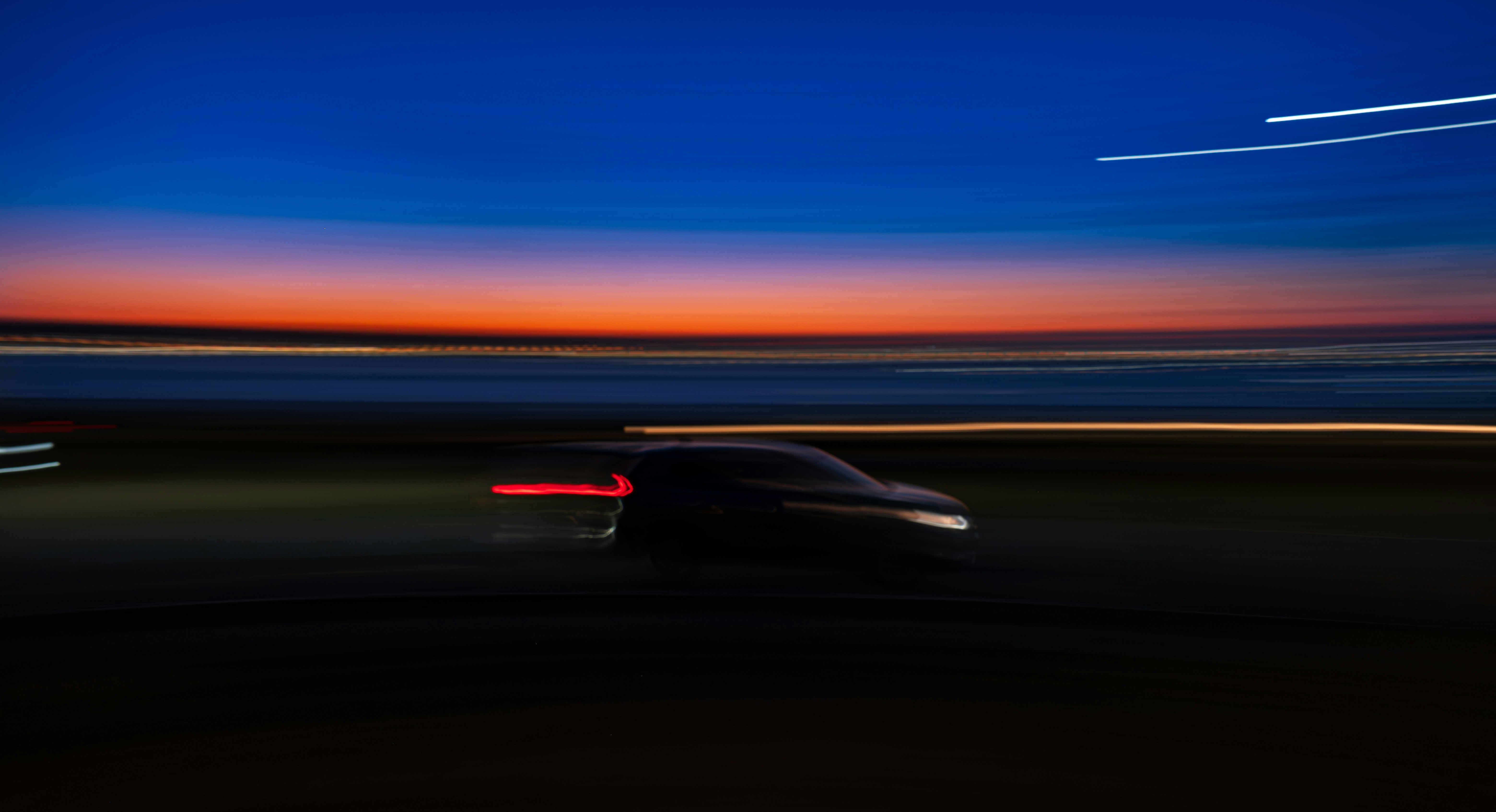 speeding car on highway | Car driving at dusk with light trails