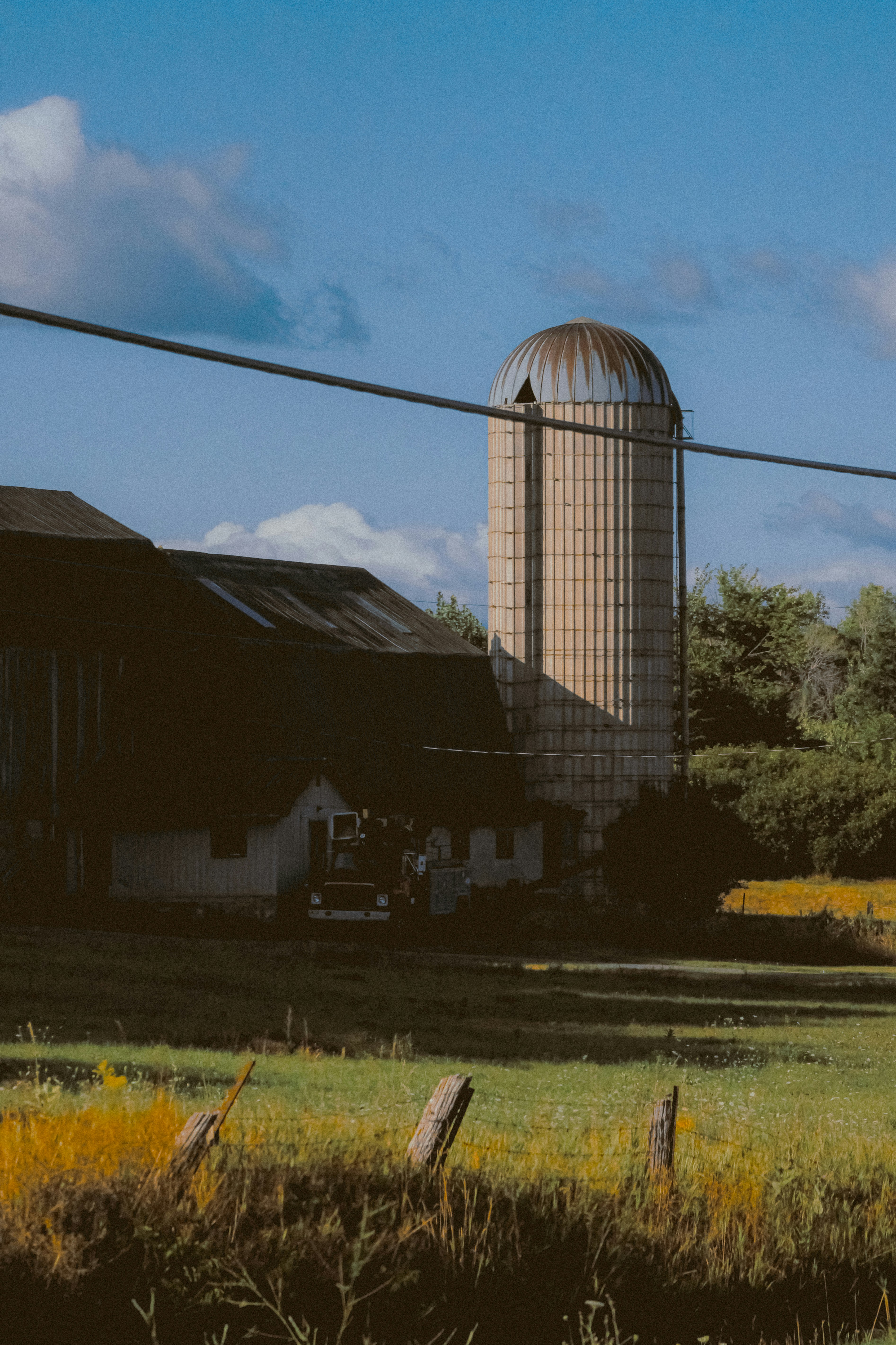 Silo in the Afternoon Light: A Quiet Farmyard Under a Blue Sky