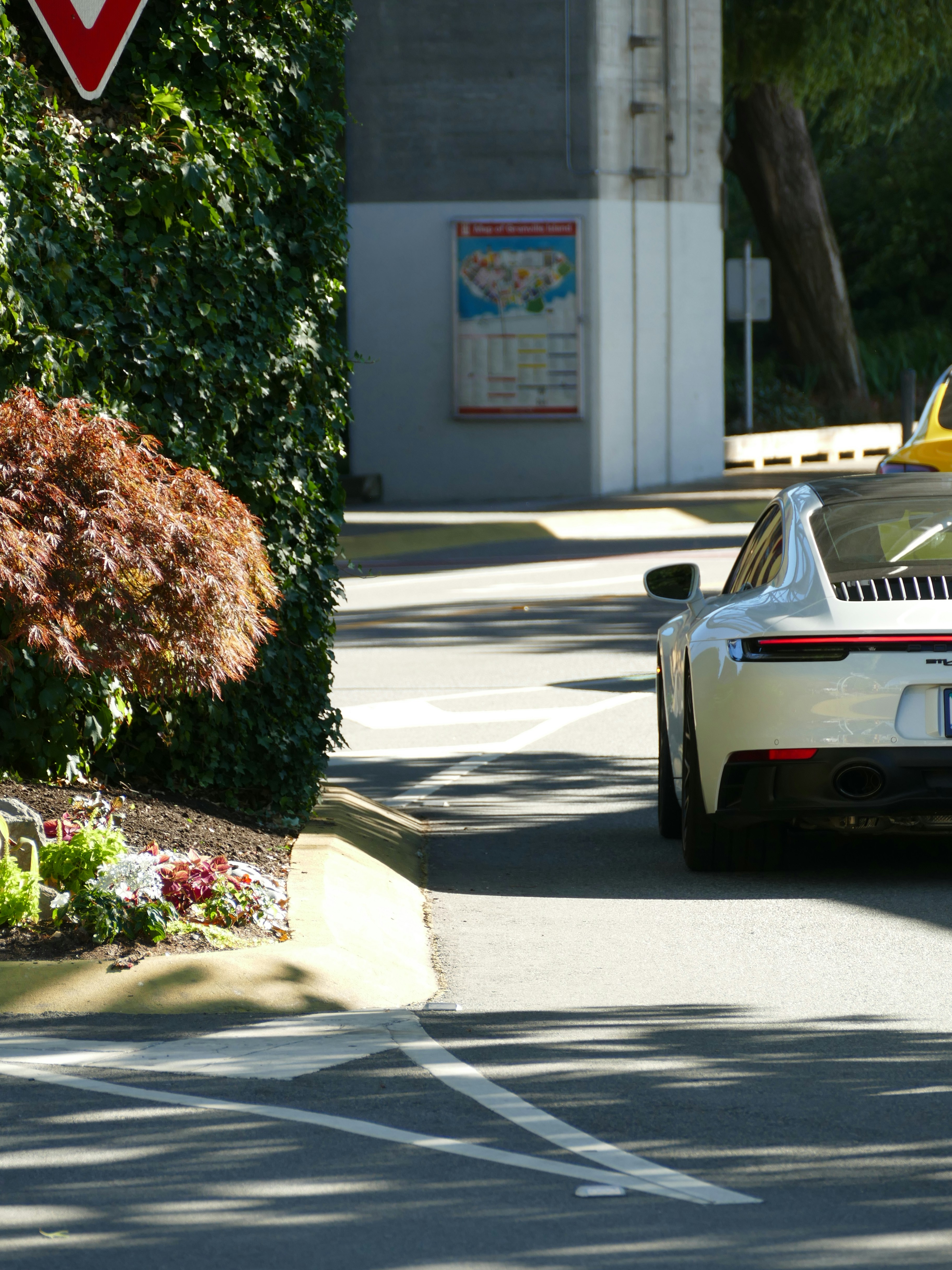 A sleek sports car navigates a winding path framed by vibrant foliage and a stop sign, illustrating the harmony between technology and nature.