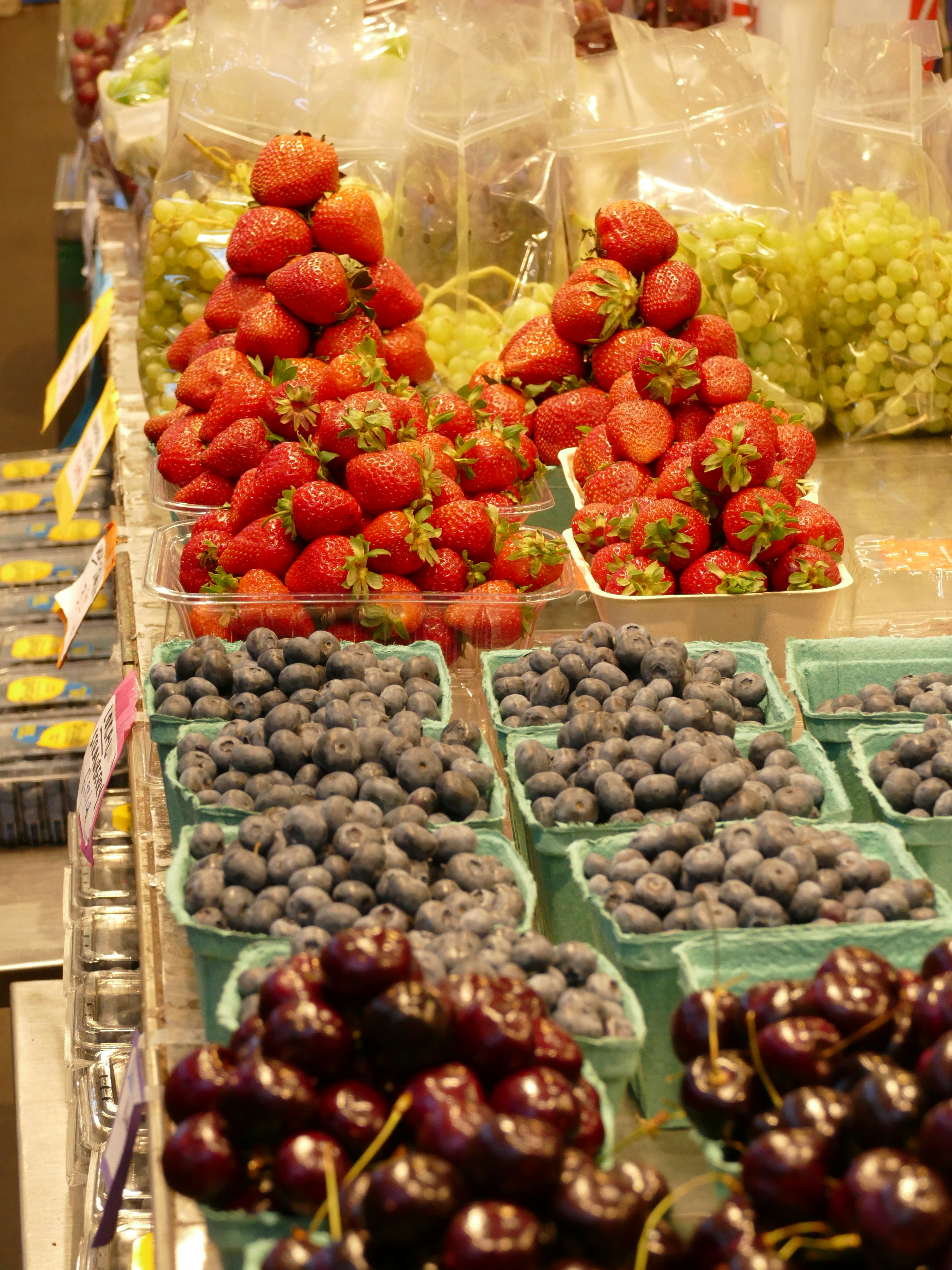 Fresh strawberries, blueberries, grapes, and cherries displayed at market.