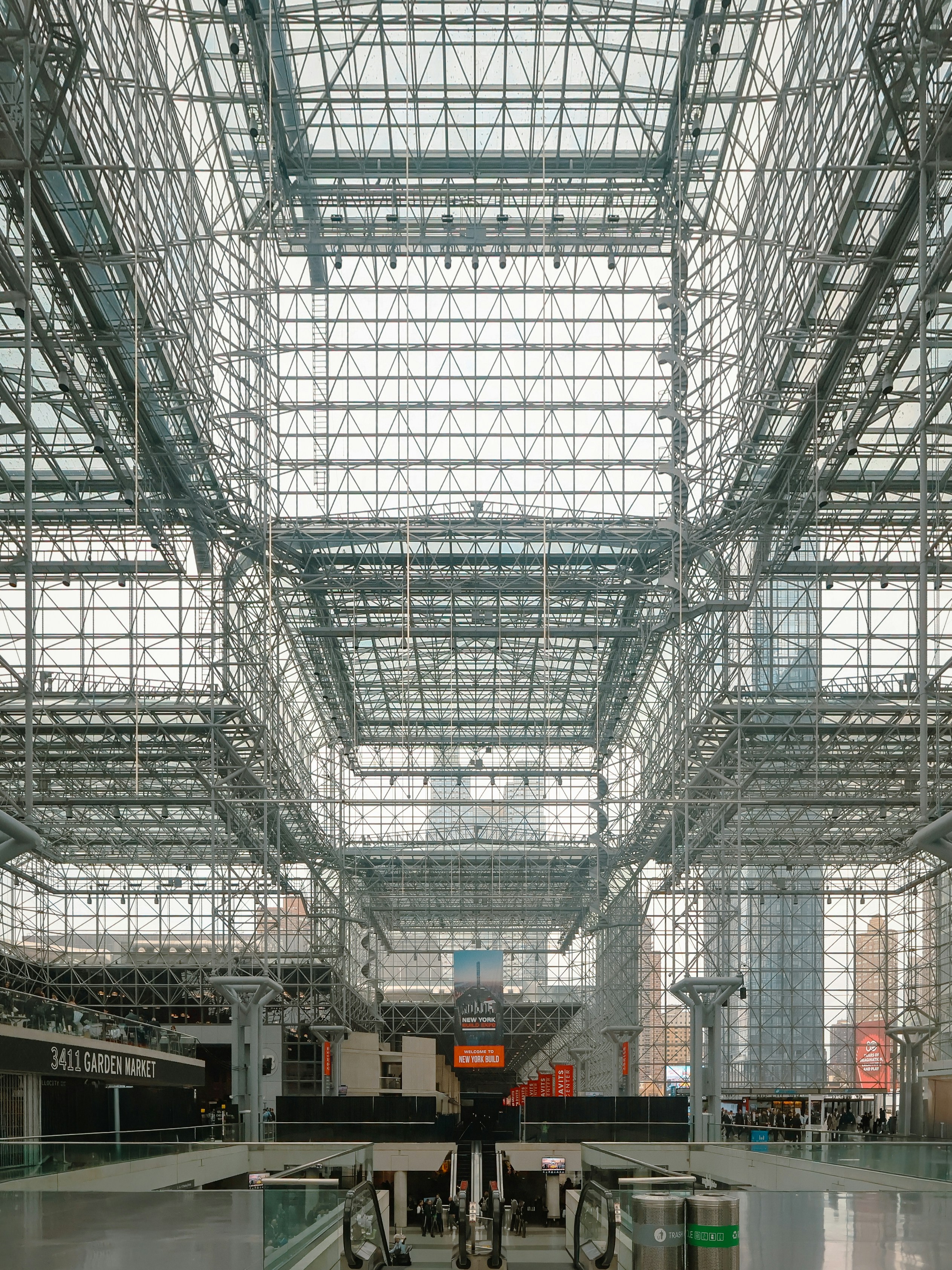 Lobby of the Javits Center. | Modern glass and steel atrium with escalators and city buildings.