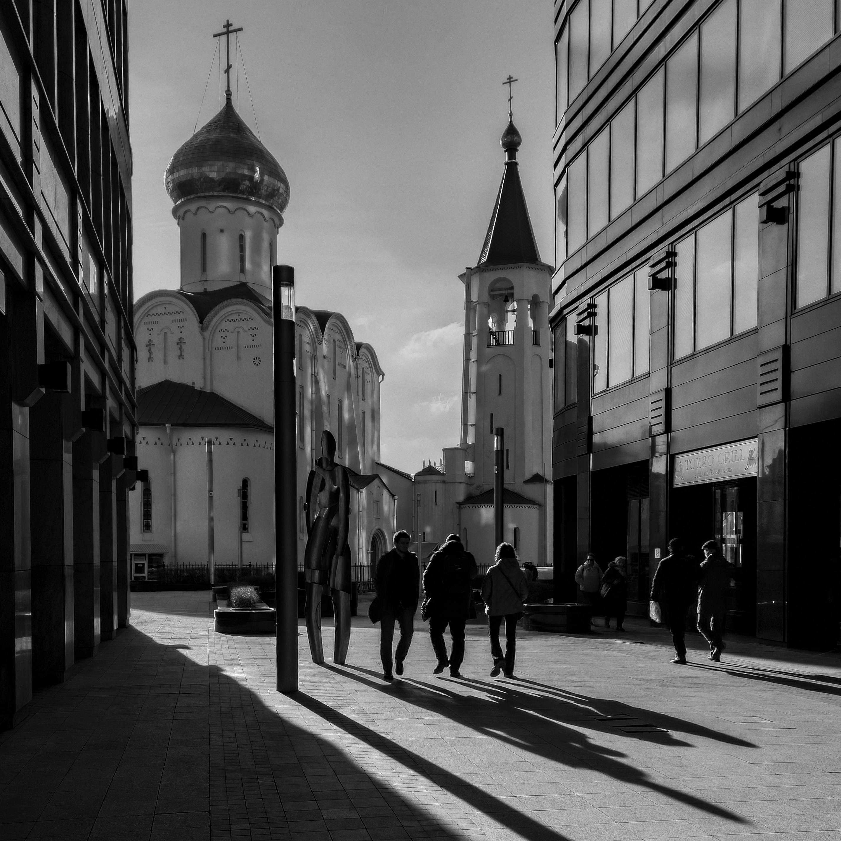 People walk down a street towards a church.