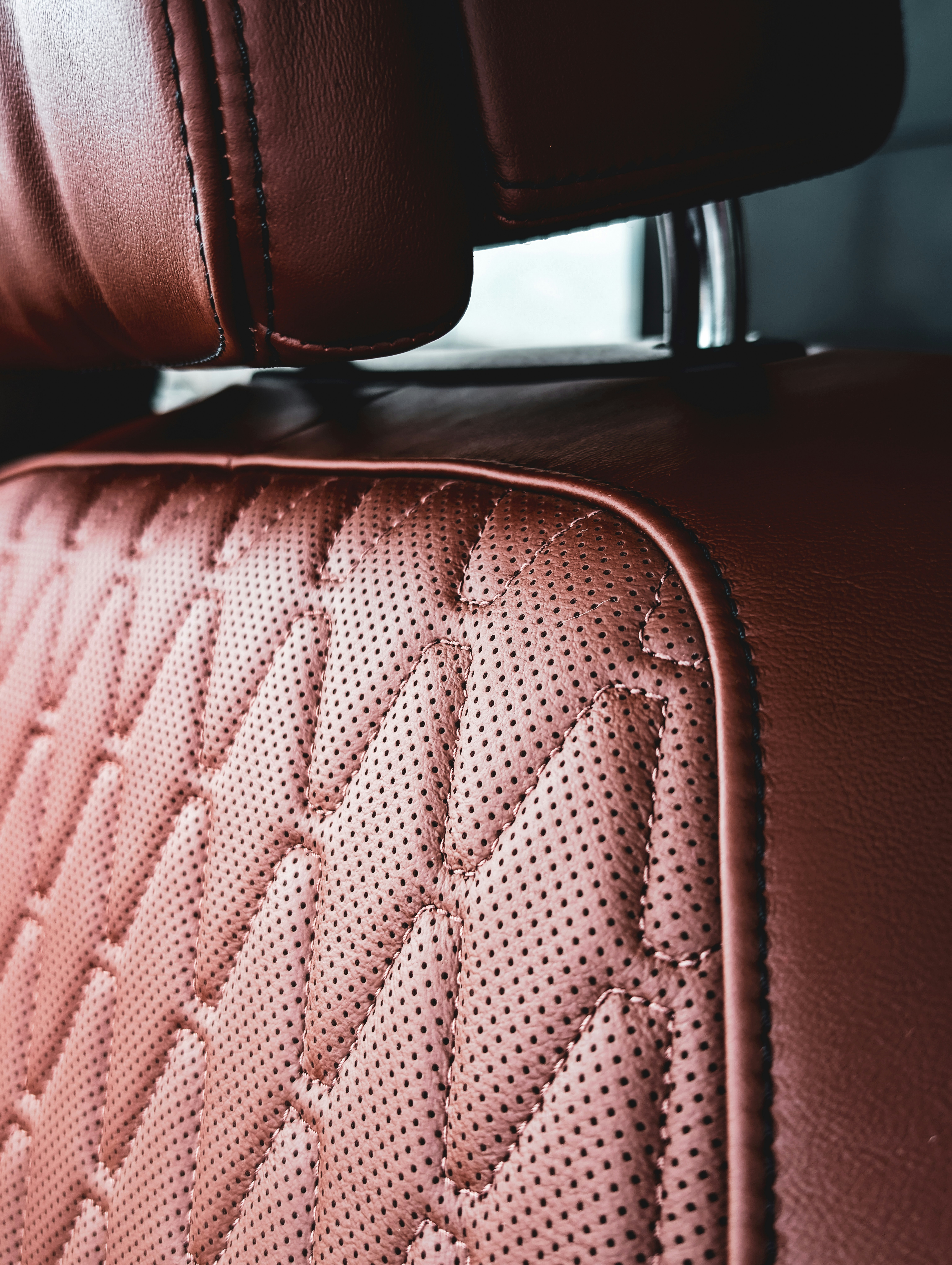 An intimate look at superior automotive design, this photo highlights the rich texture of diamond-quilted, perforated red leather, embodying the very essence of high-end comfort and meticulous craftsmanship.