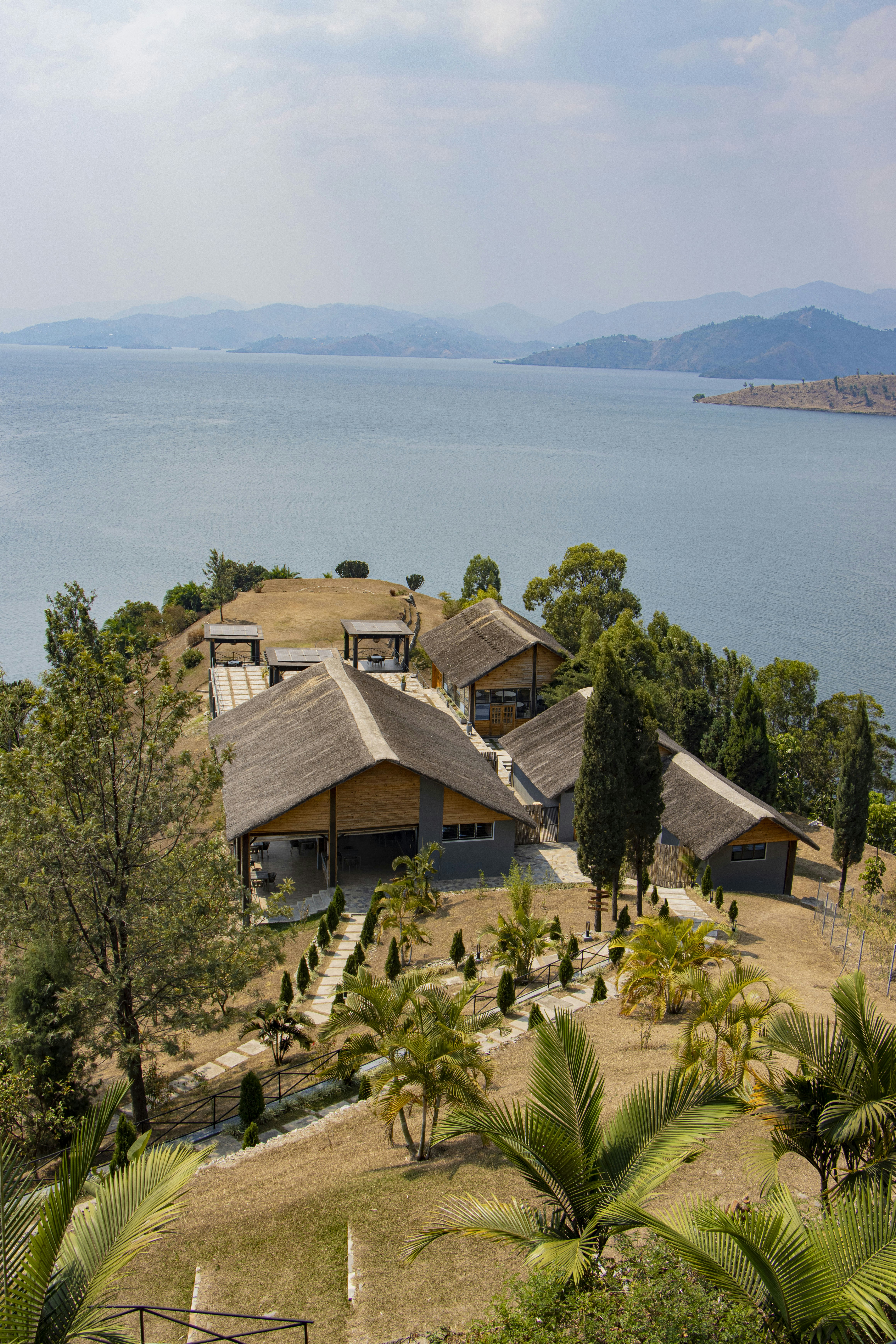 Thatched Lodges Beside a Tranquil Lake, Framed by Hills
