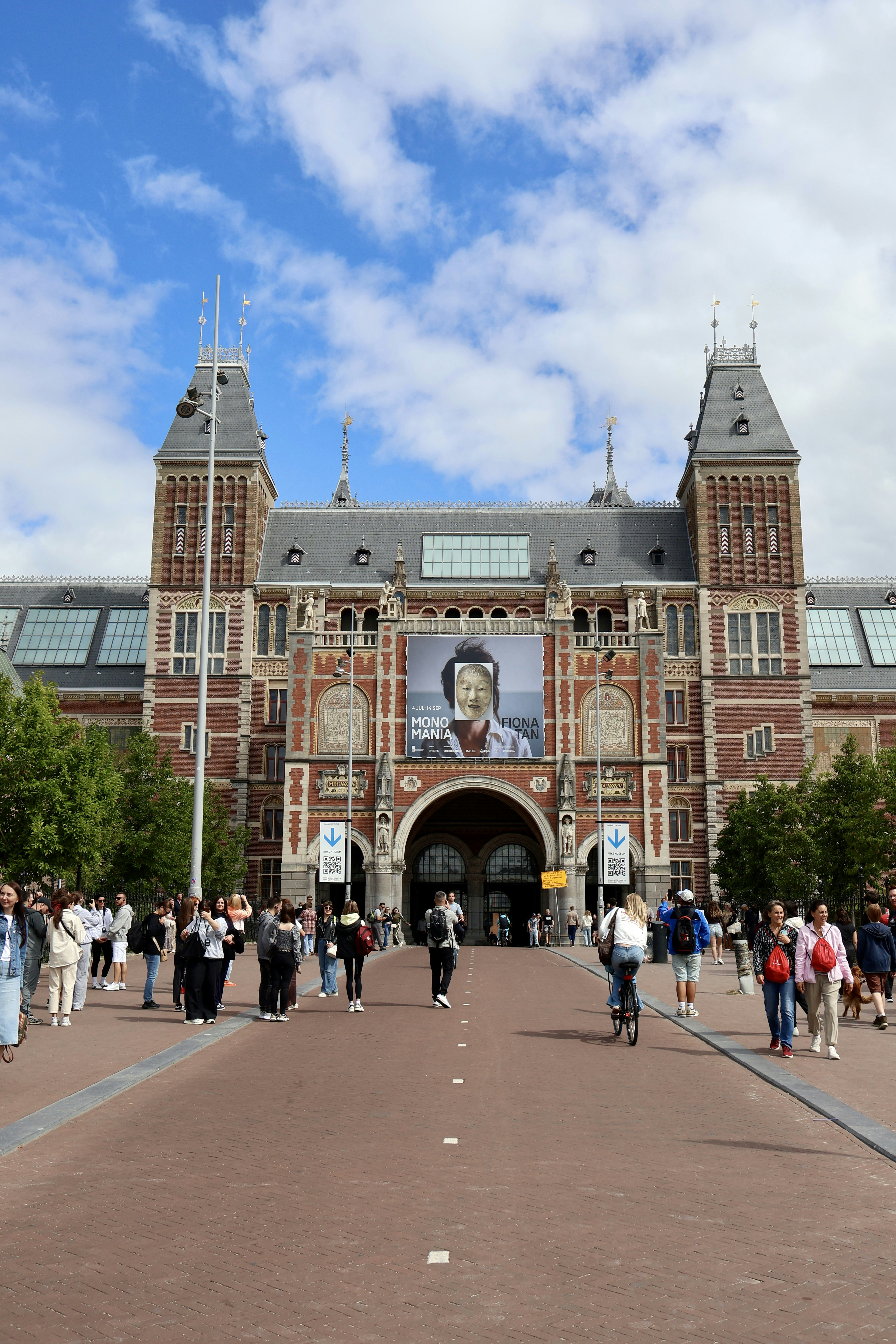 People walk towards a large historic building with a banner.