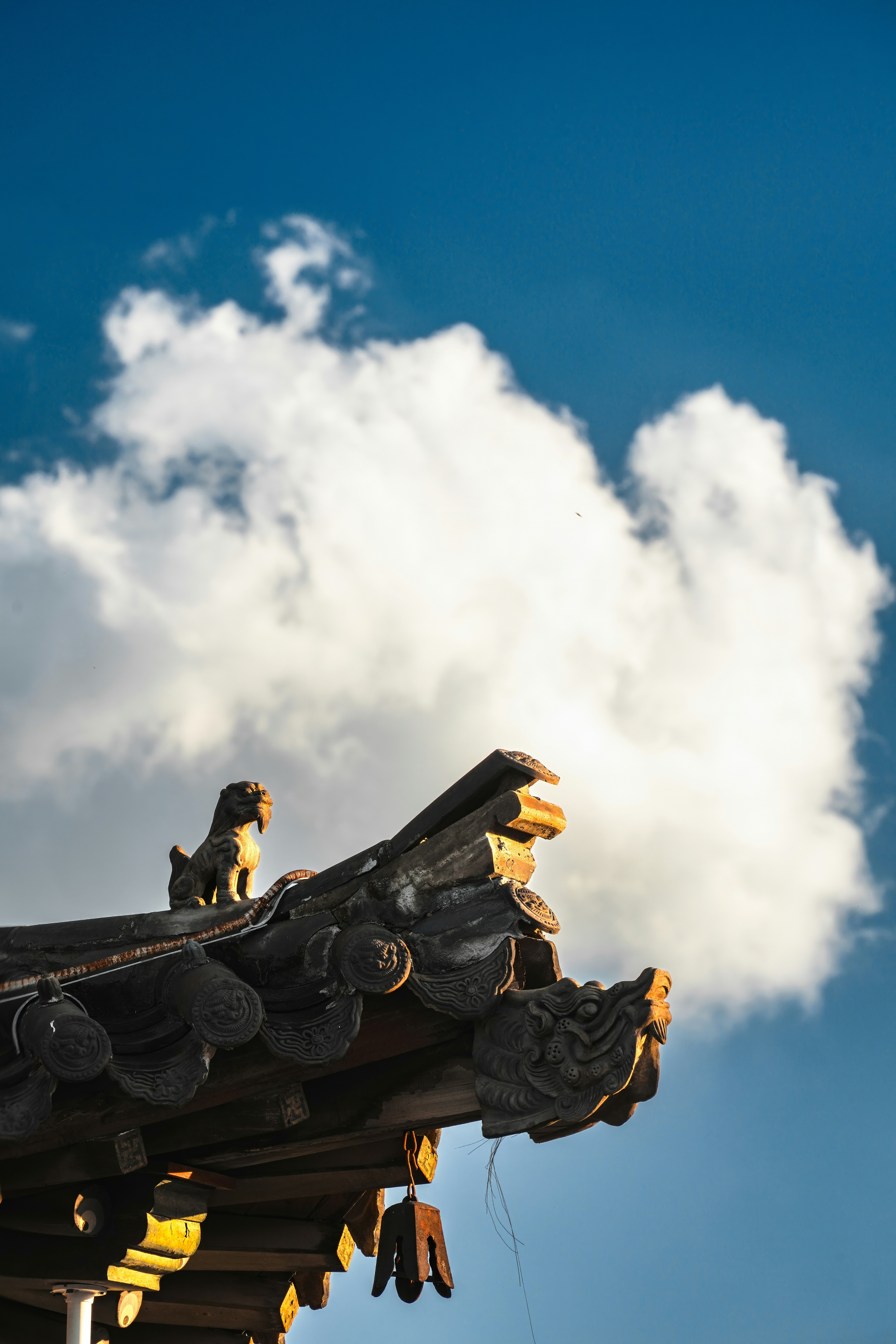 Ornate roof detail with a small statue against blue sky.