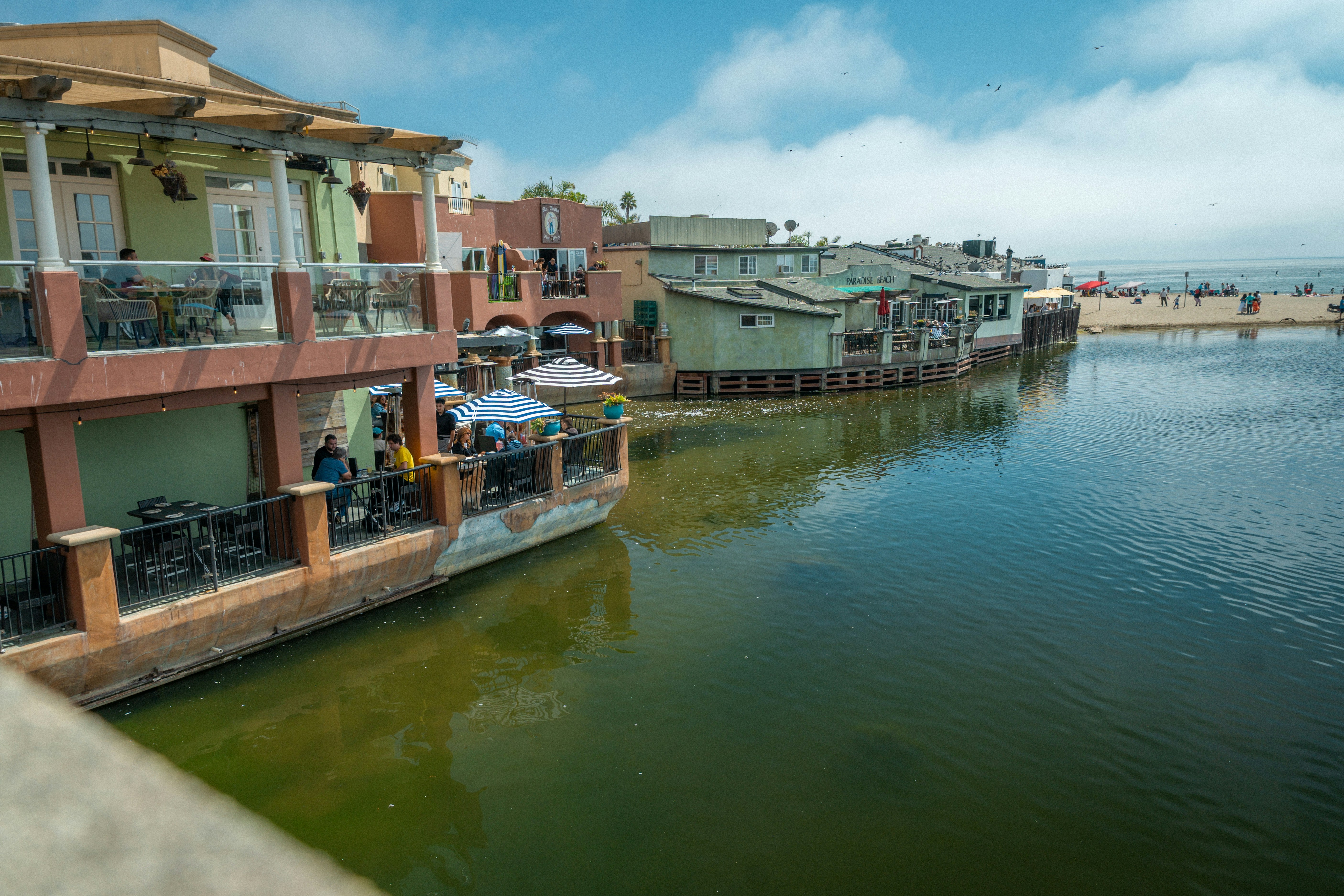 Colorful buildings line a canal with people on the beach.