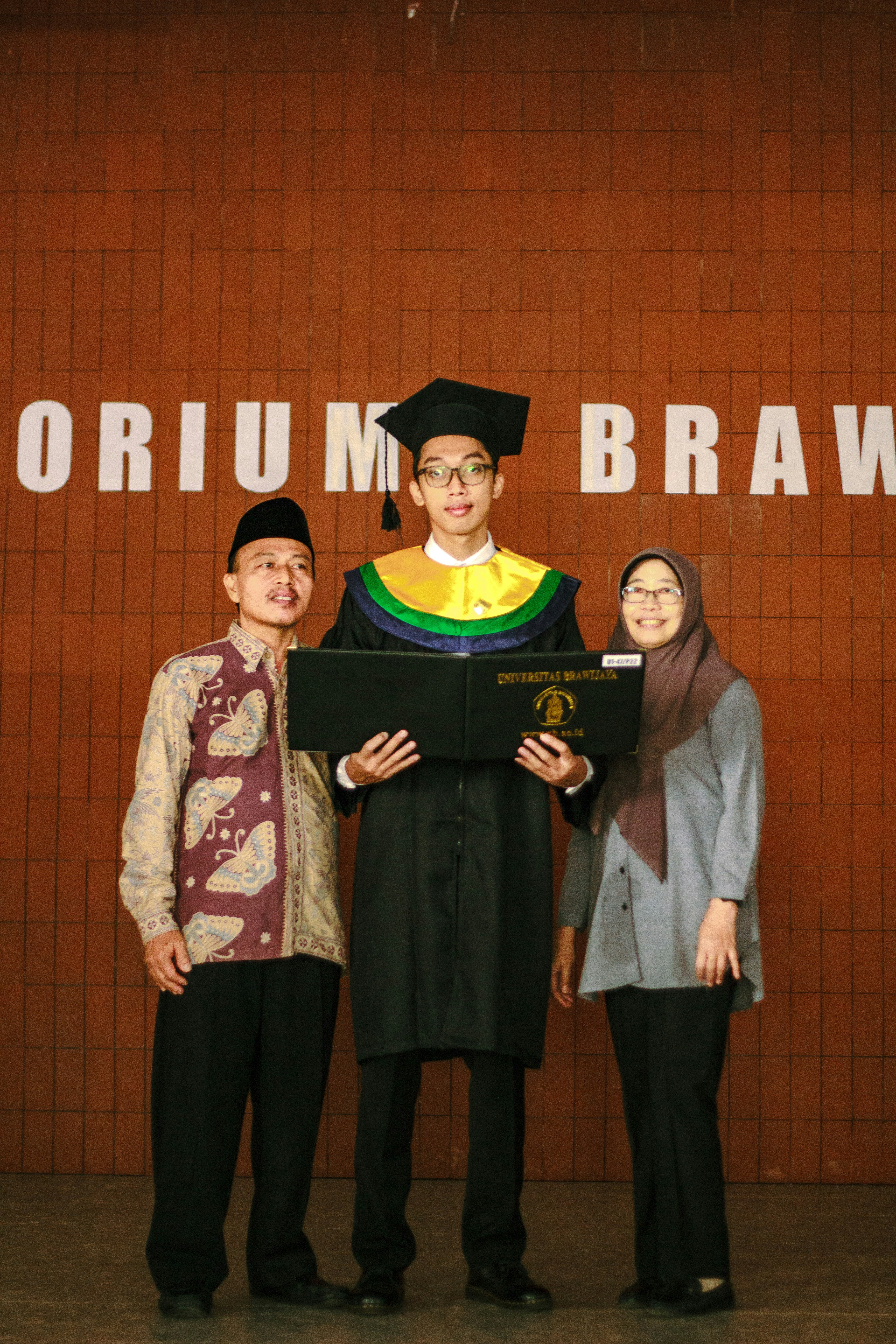 Graduating student with parents holding diploma and parents