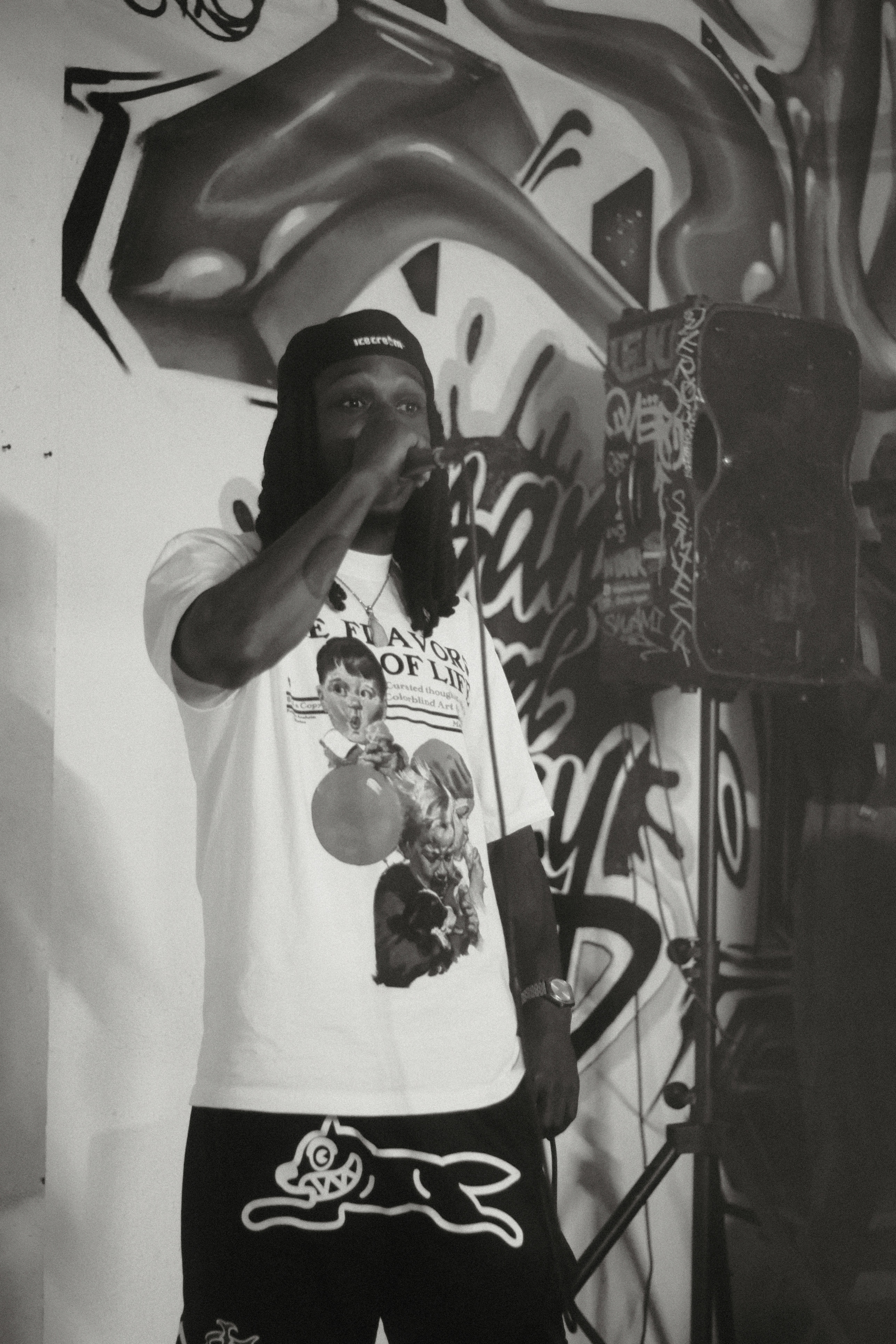 A man rapping into a microphone with graffiti in background photo ...