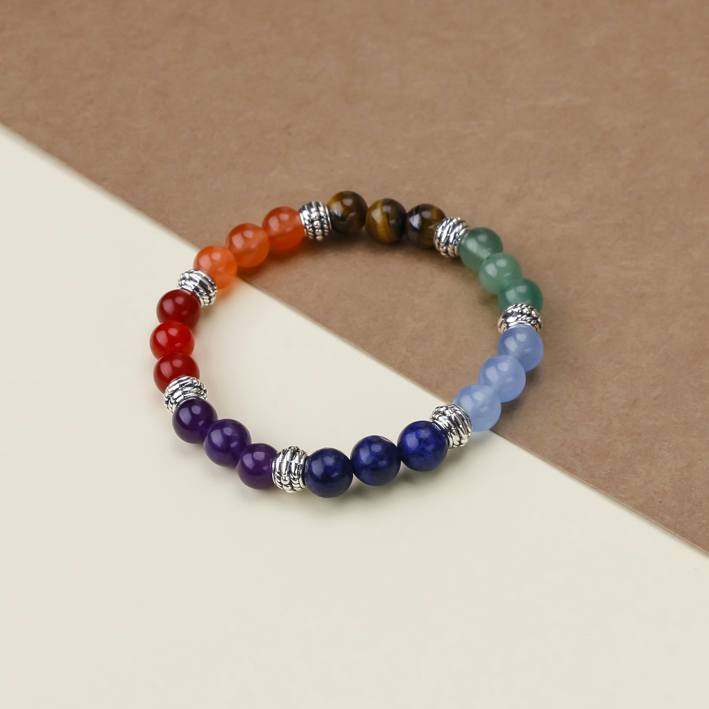 Colorful gemstone bracelet featuring a variety of stones, arranged in a circular design with silver accents. The contrasting backgrounds enhance the vibrant hues.