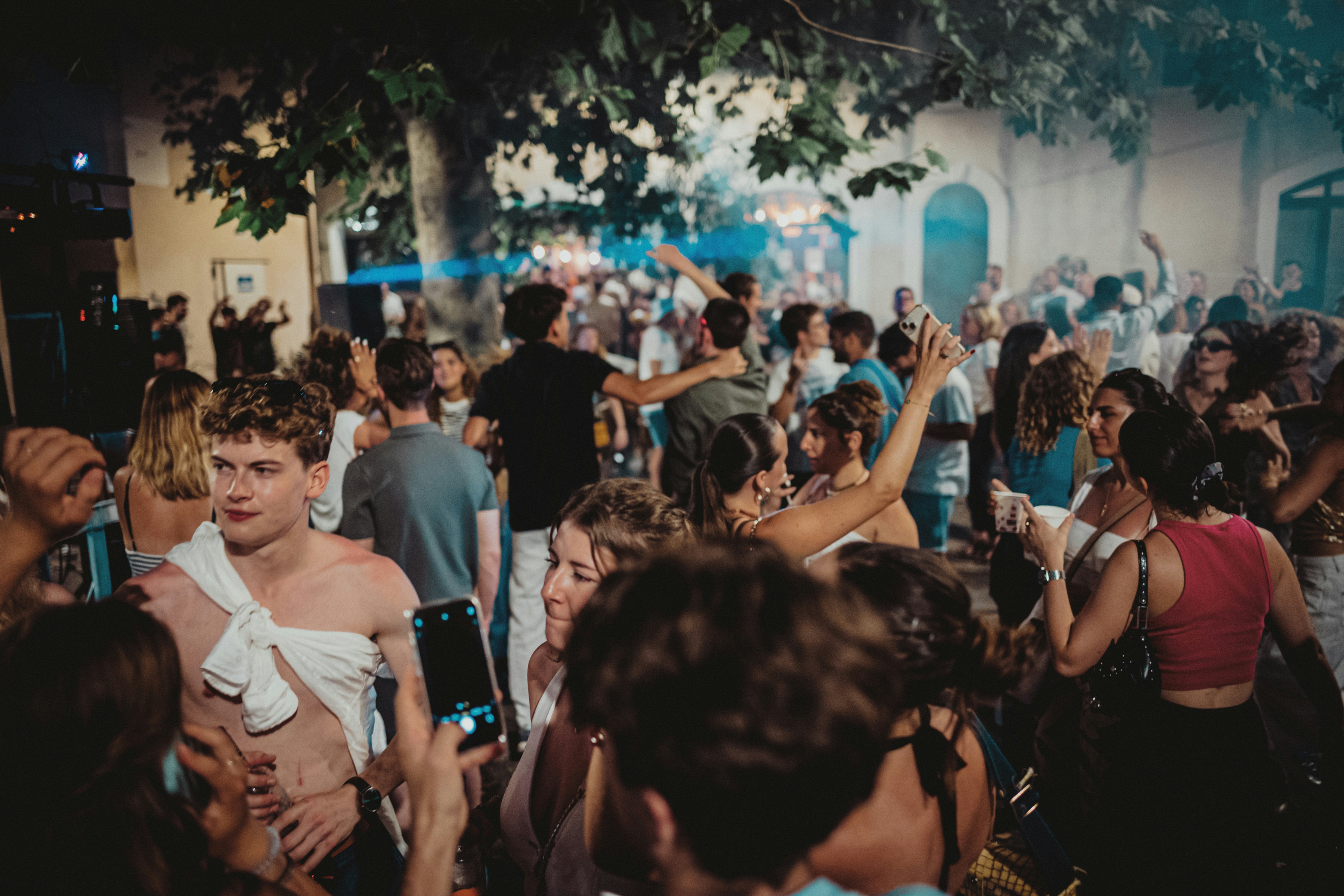 Crowd of people dancing at an outdoor nighttime event.