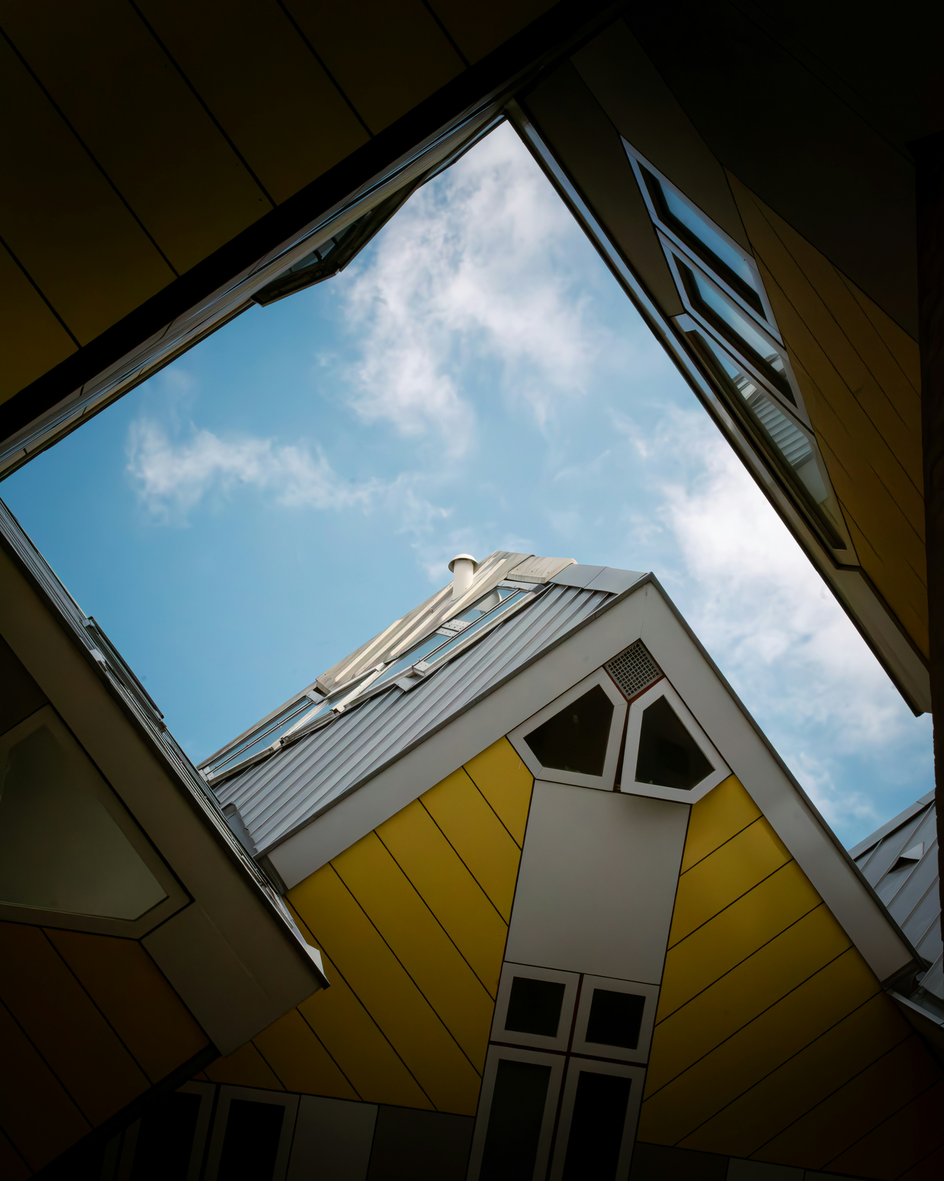Unique architectural angles framed by vibrant yellow and gray buildings, showcasing a clear blue sky above.
