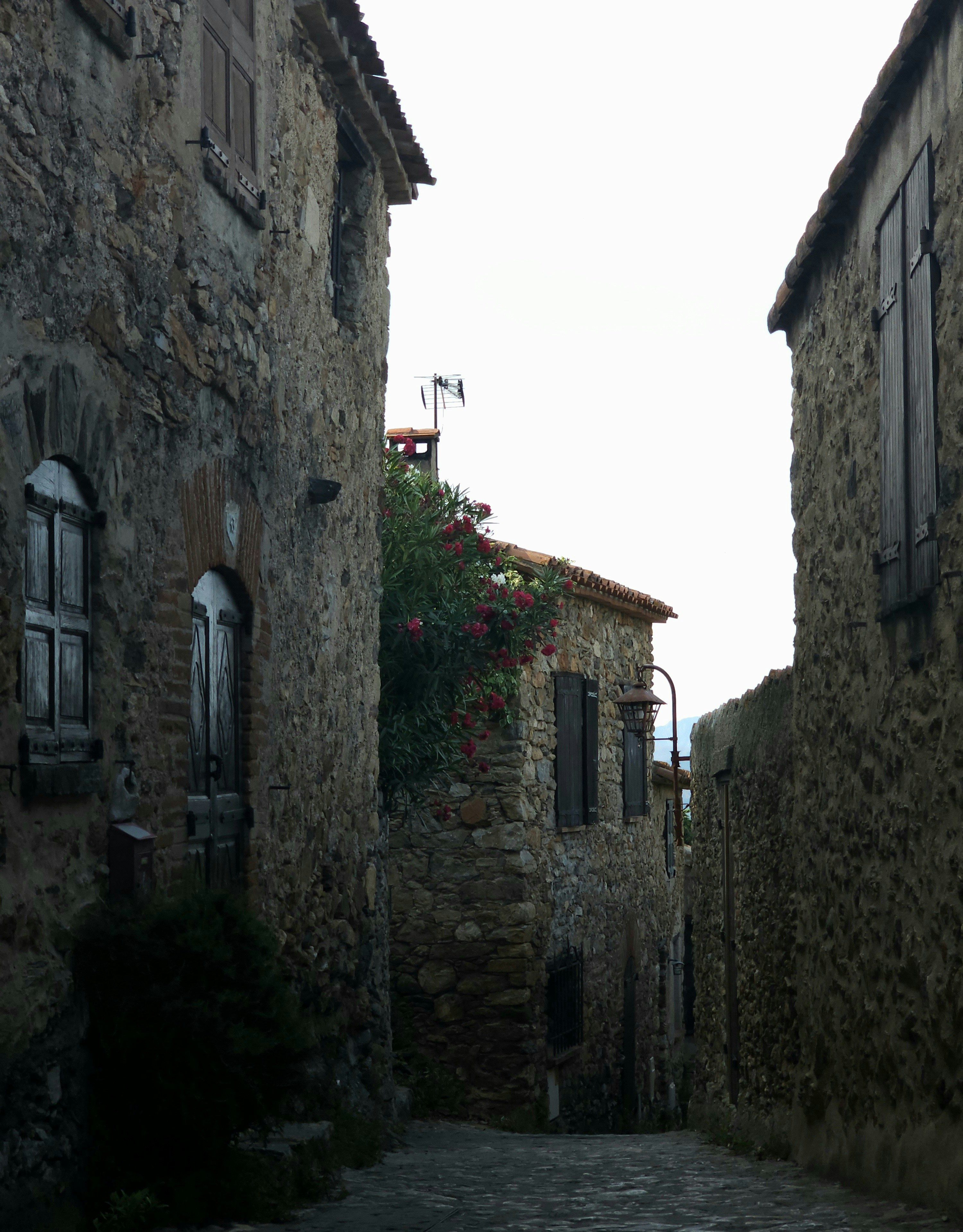 Narrow cobblestone street between stone buildings.
