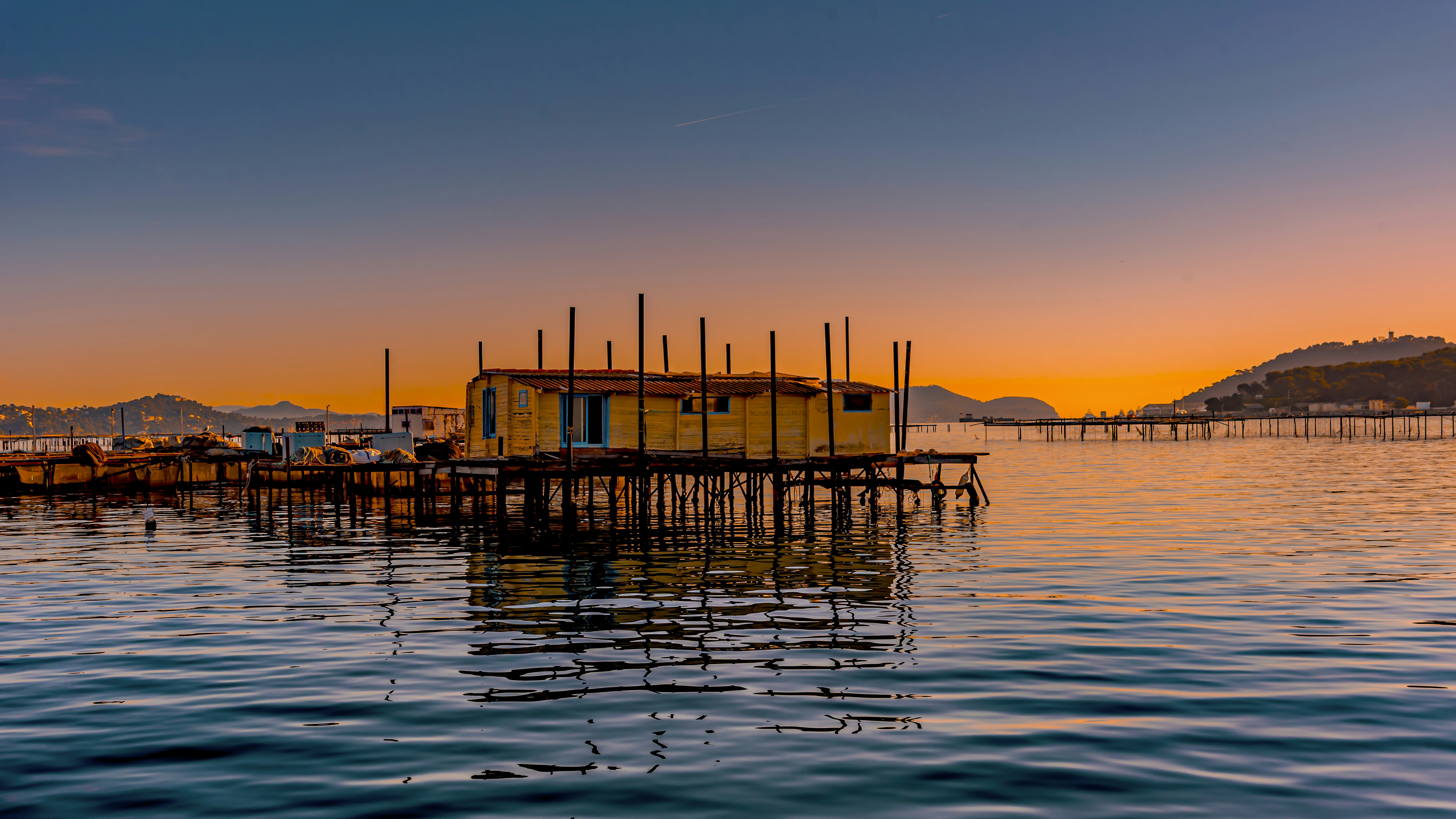 Yellow stilt house on water at sunset