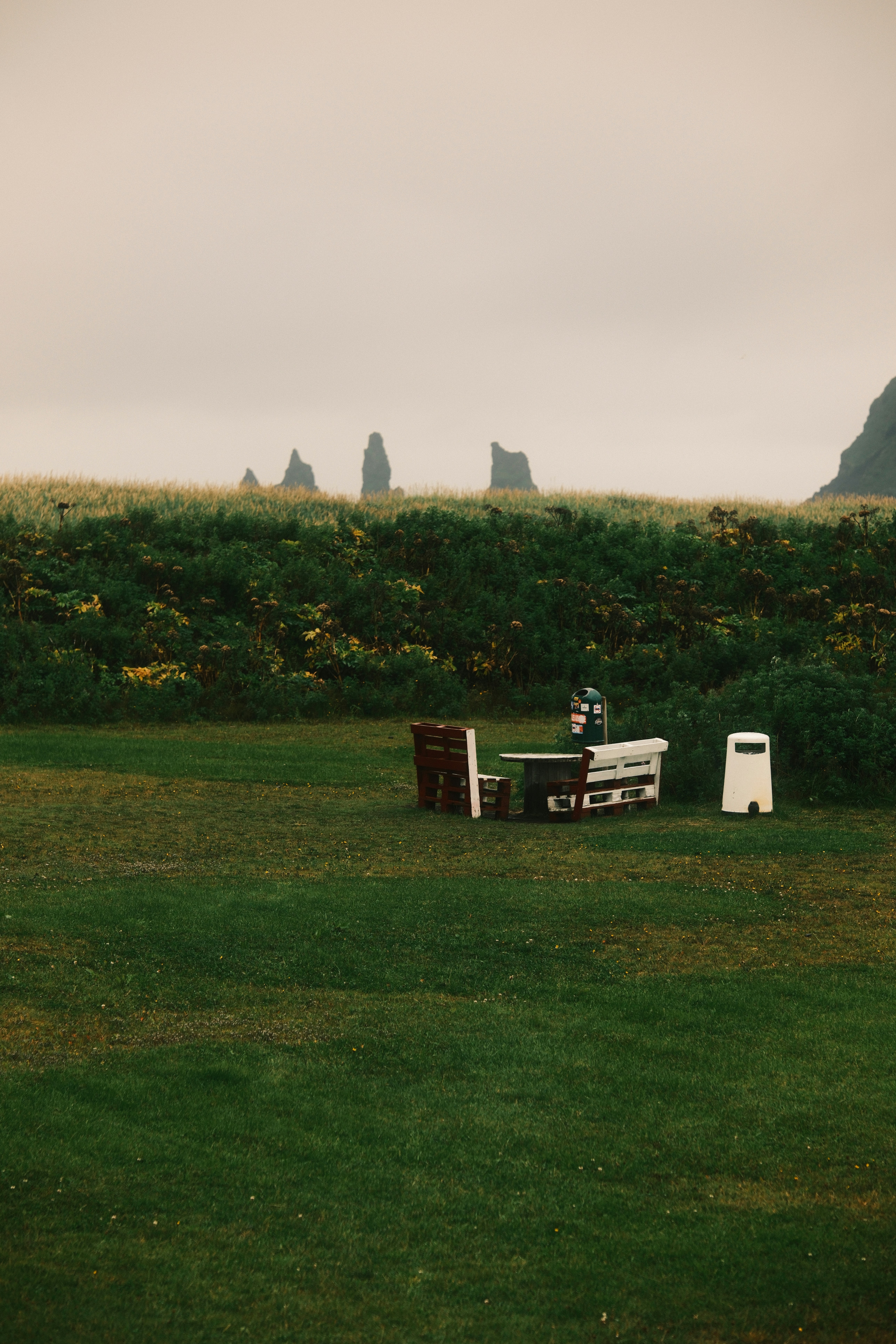Wooden seating area on a grassy field with rugged rock formations in the background. The scene evokes a sense of tranquility and connection to nature.