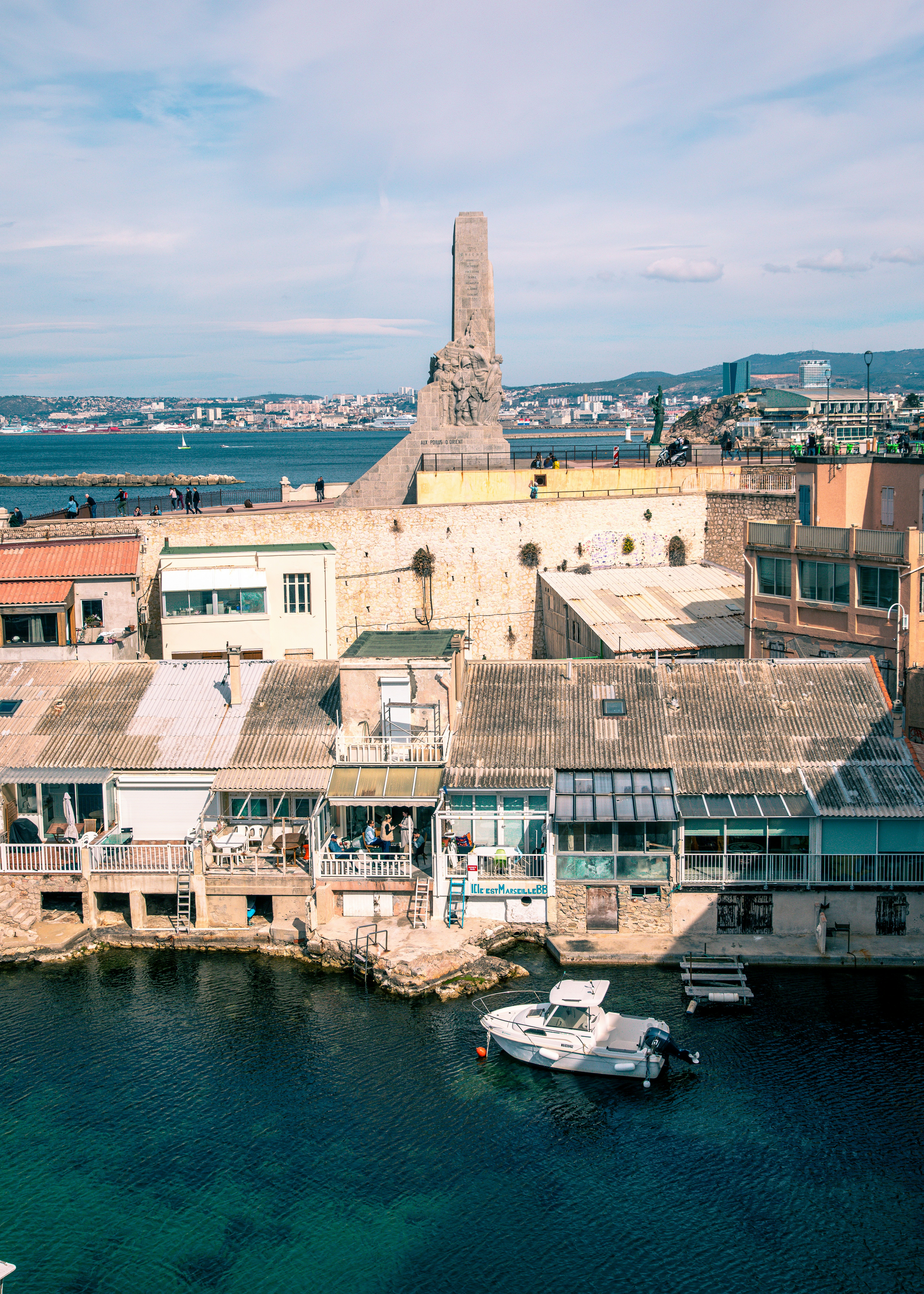 Boats docked in a harbor with historic buildings and monument.