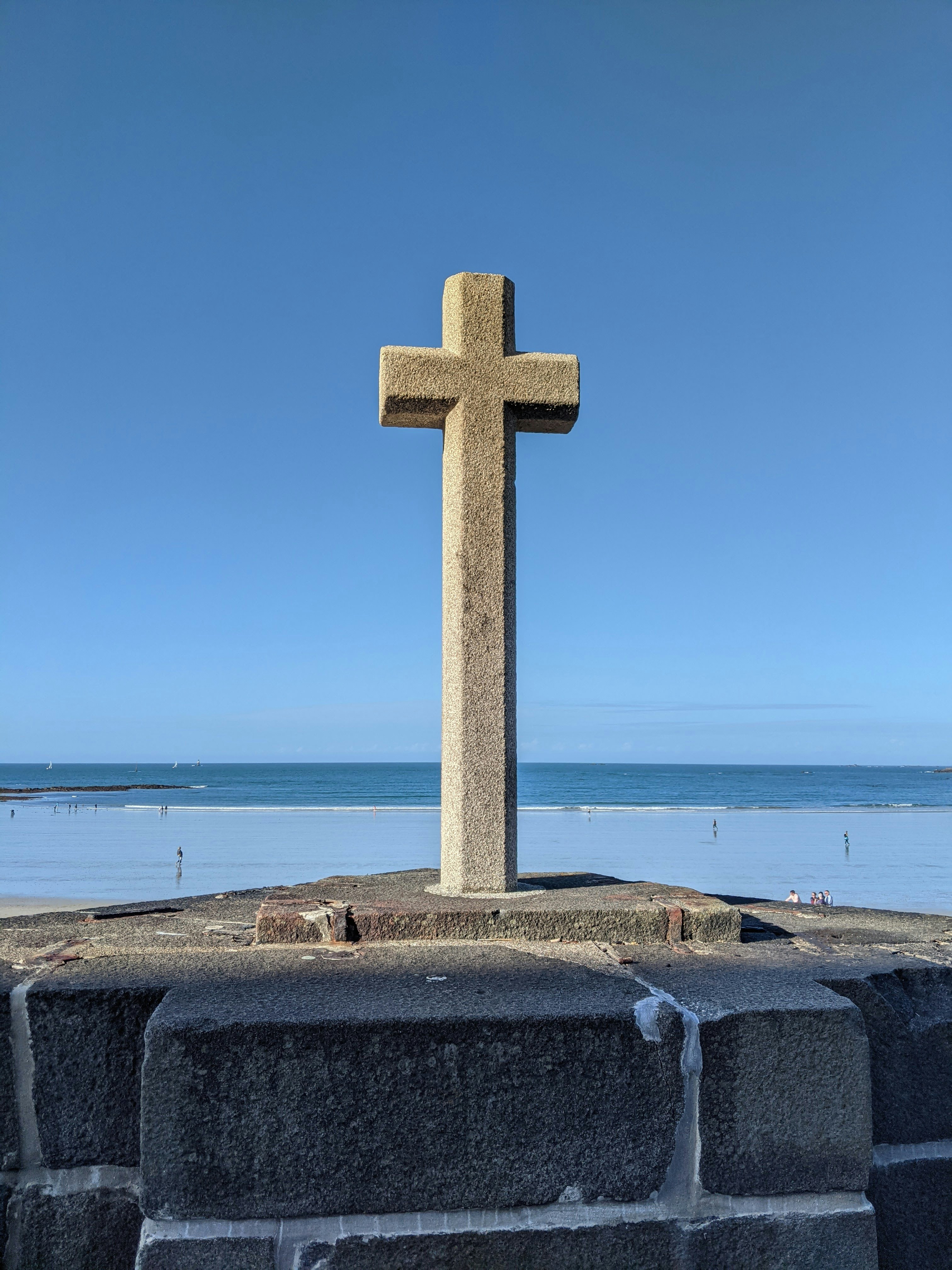 A cross on the beach in St. Malo, France | Stone cross on a wall overlooking the ocean