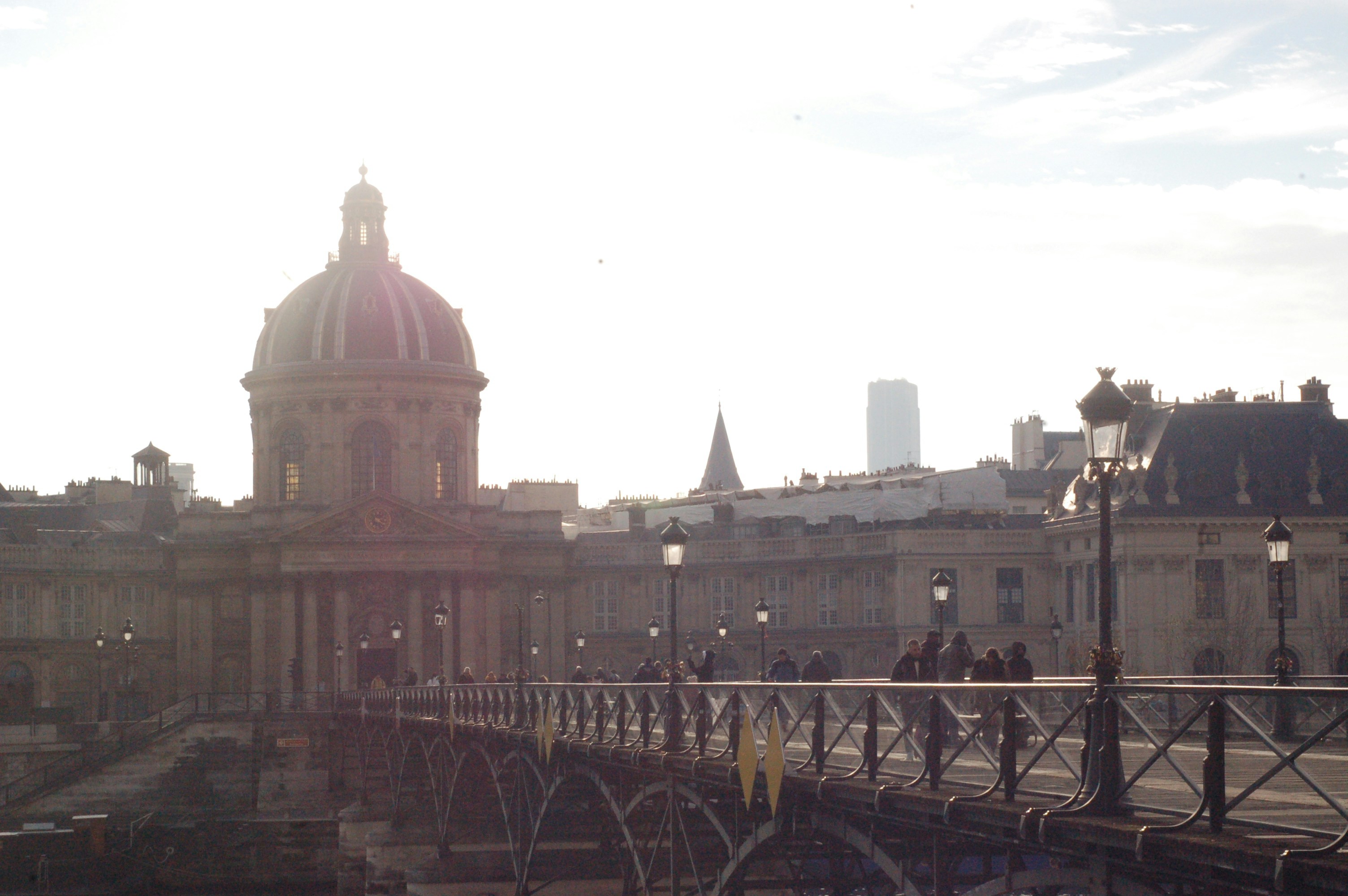 Historic bridge bustling with pedestrians, framed by a majestic dome and modern skyline in the background.
