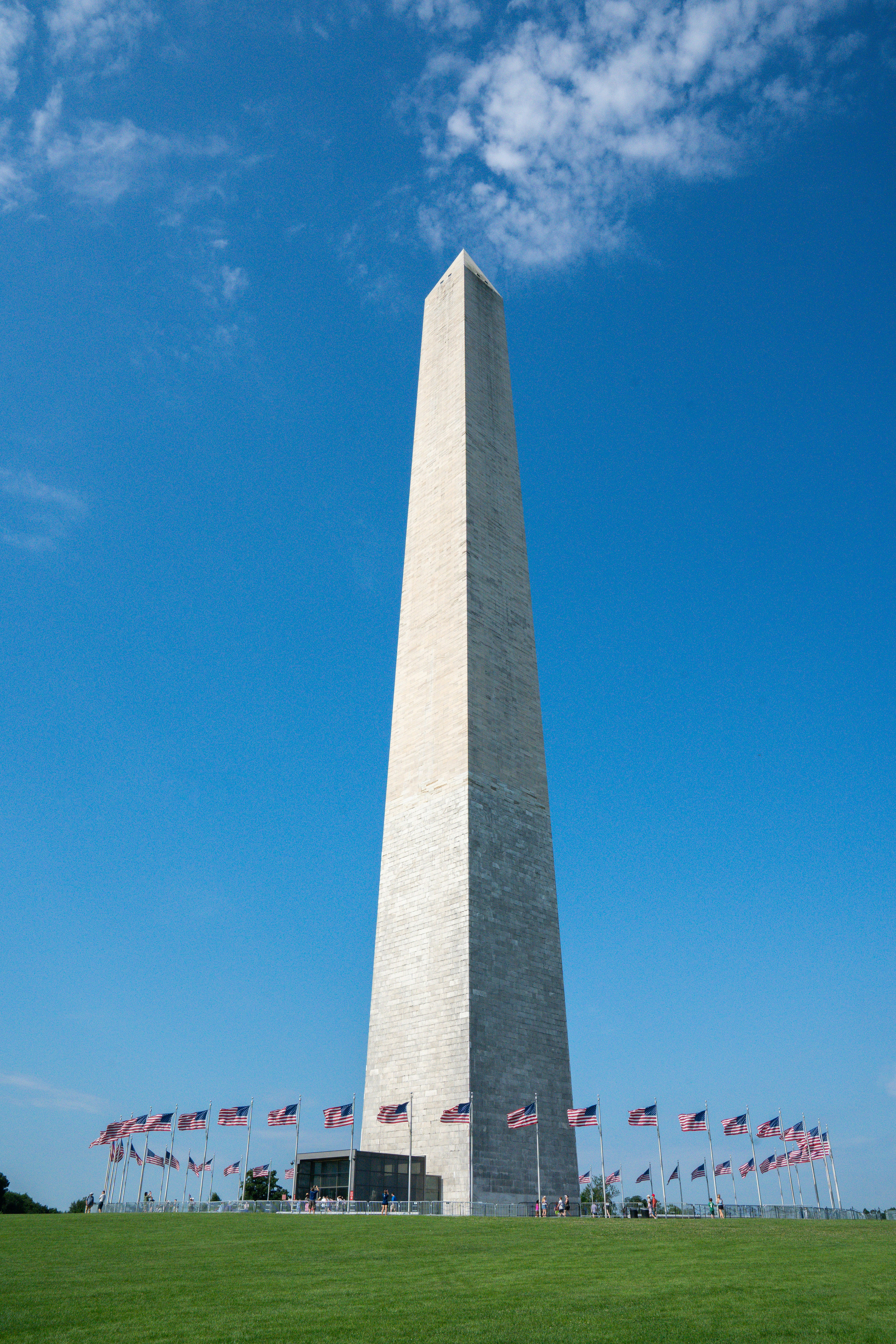 Washington monument surrounded by american flags under blue sky