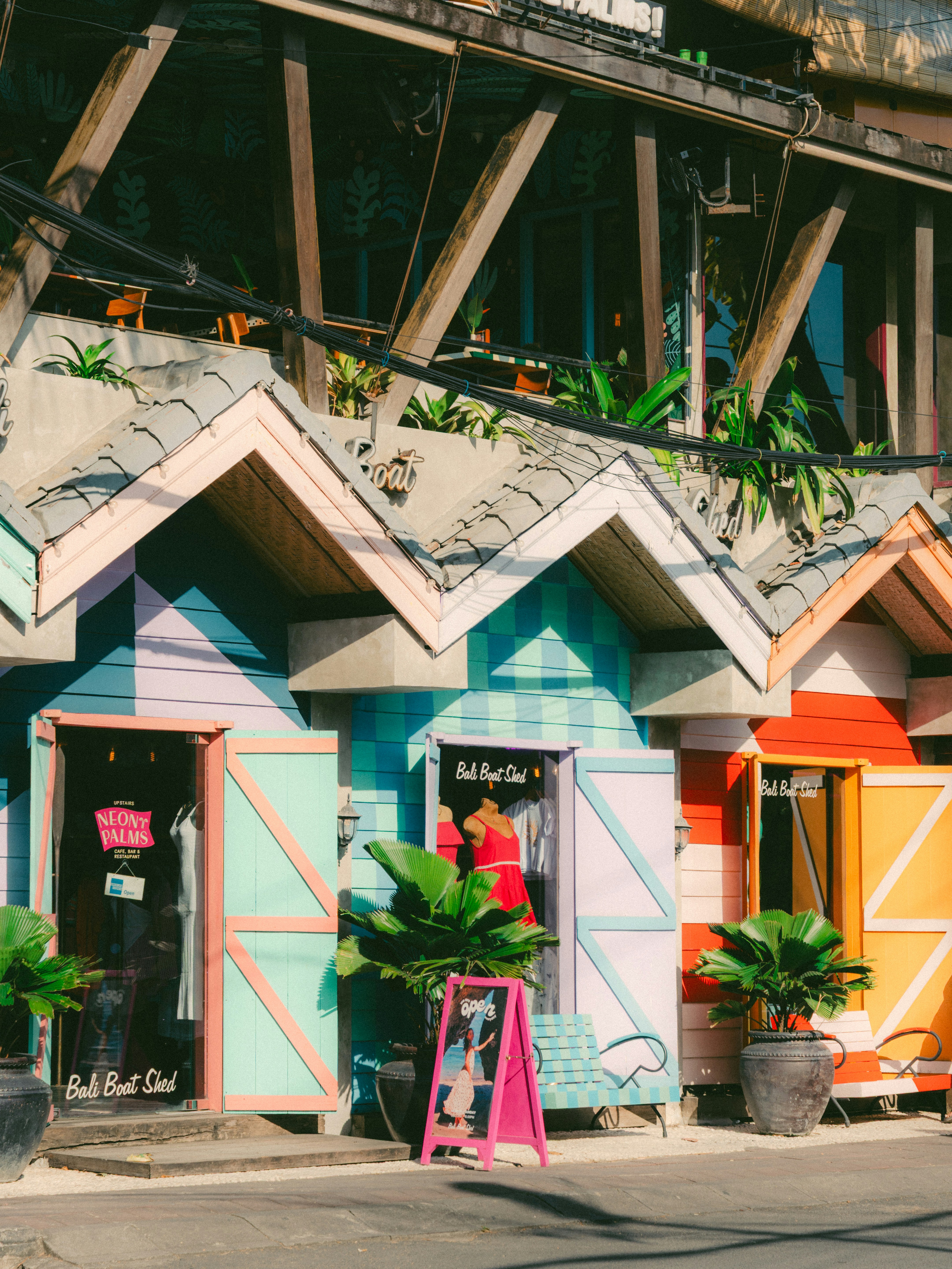 Colorful beach huts with open doors and plants.