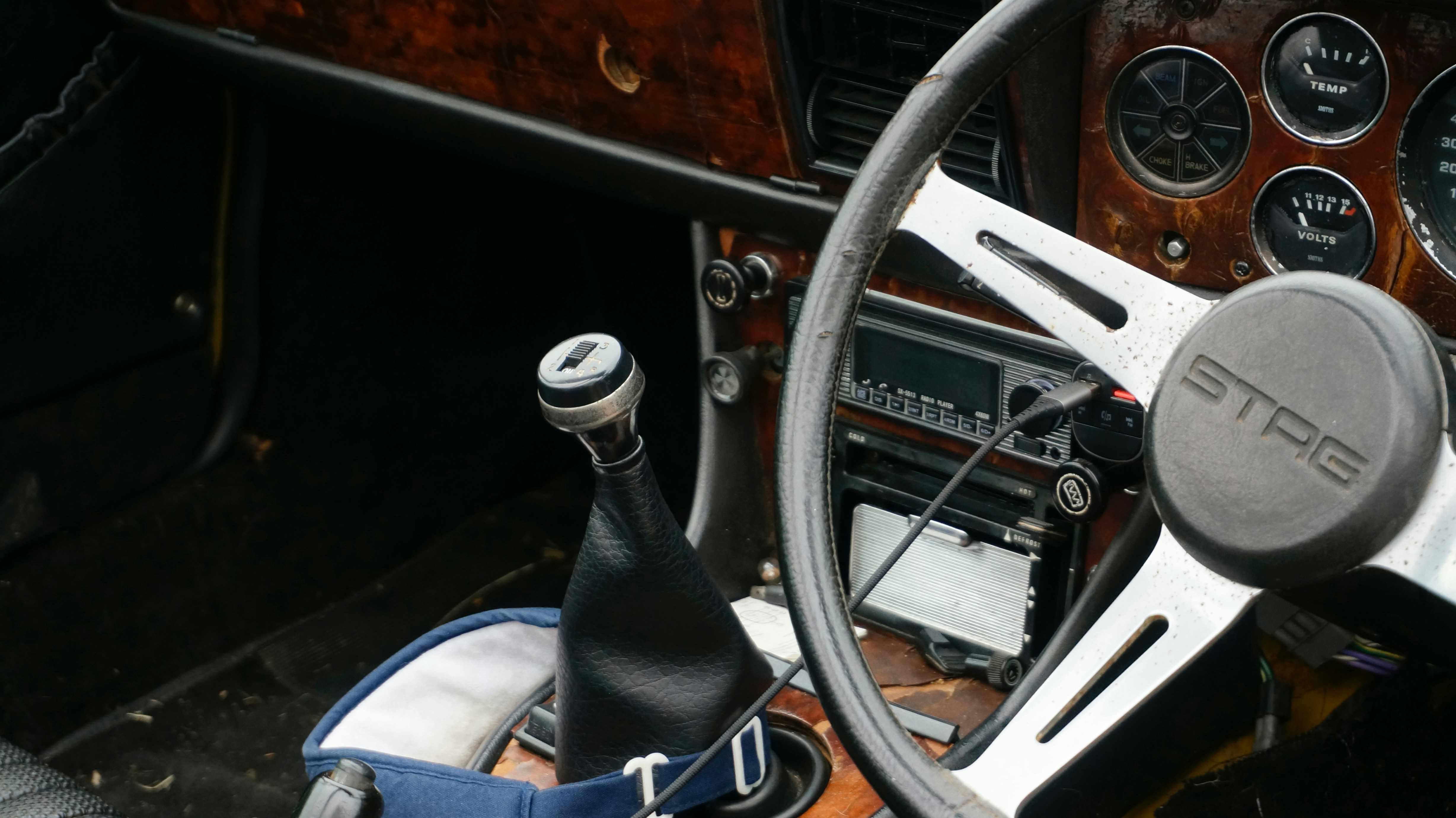Interior view of a vintage car showcasing the gear shift, steering wheel, and dashboard details, highlighting the classic design elements.