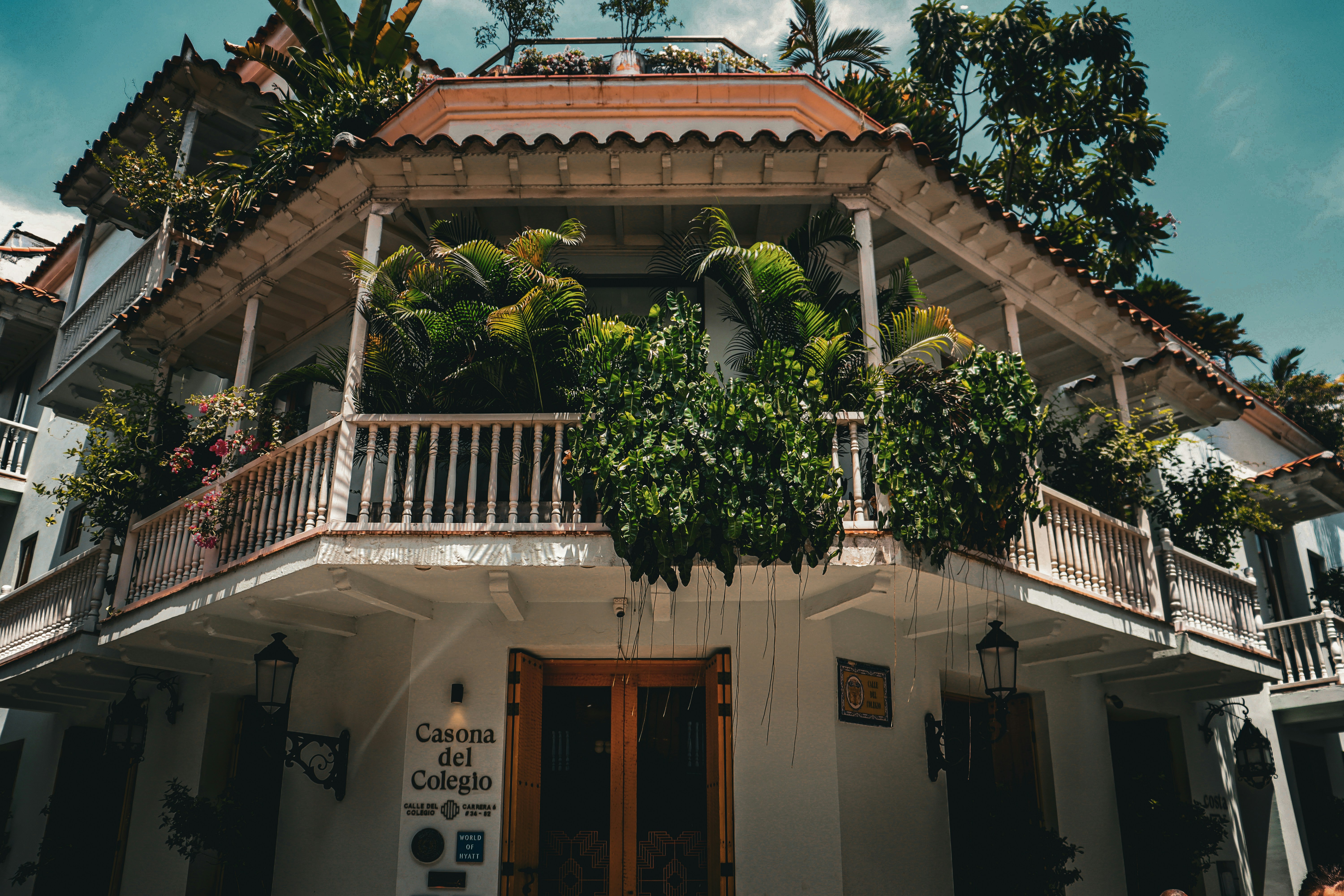 Ornate colonial building with lush green plants on balcony.