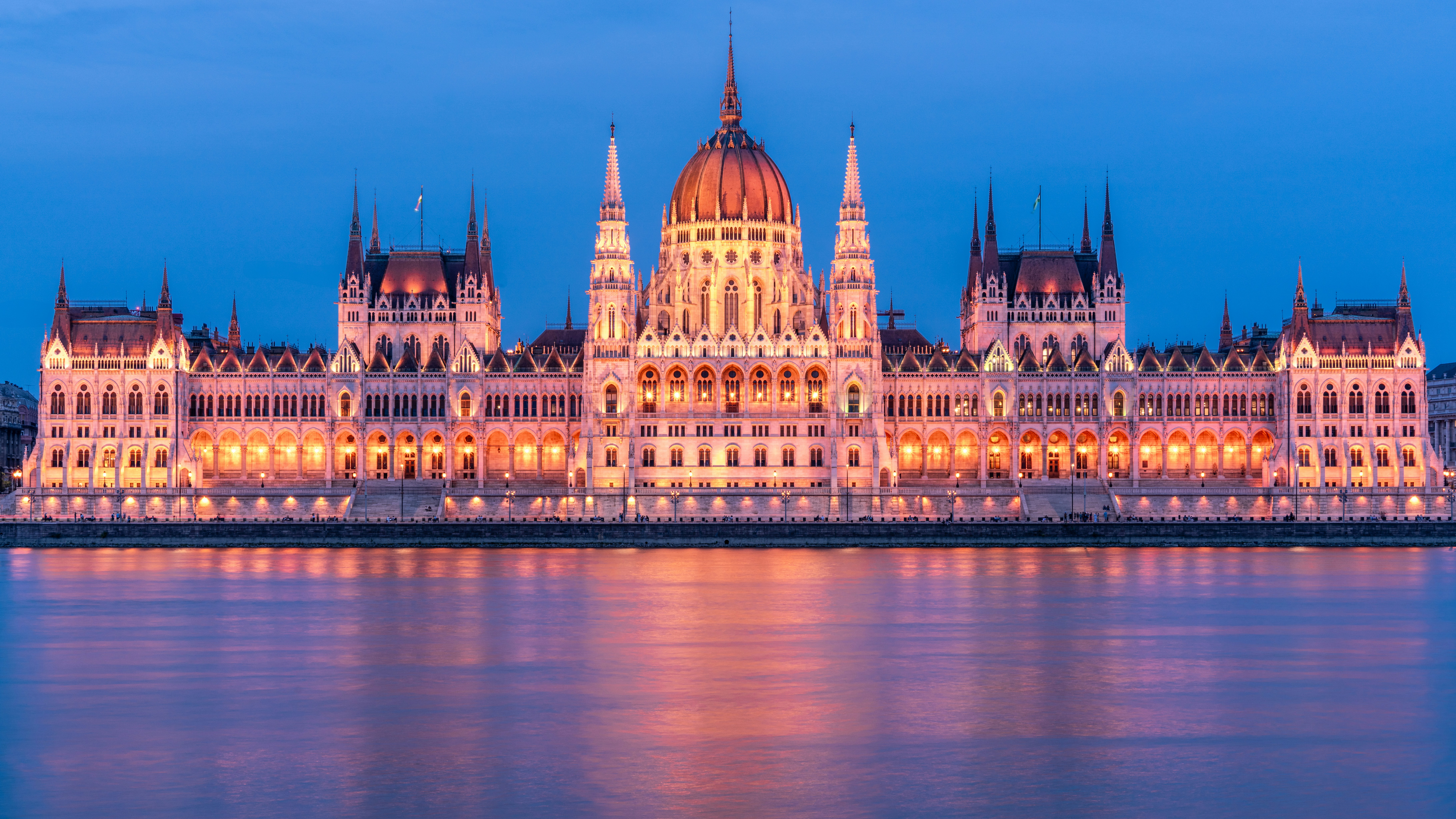 The Hungarian Parliament Building during the pinky-blue hour. | Ornate building illuminated at dusk with water reflection