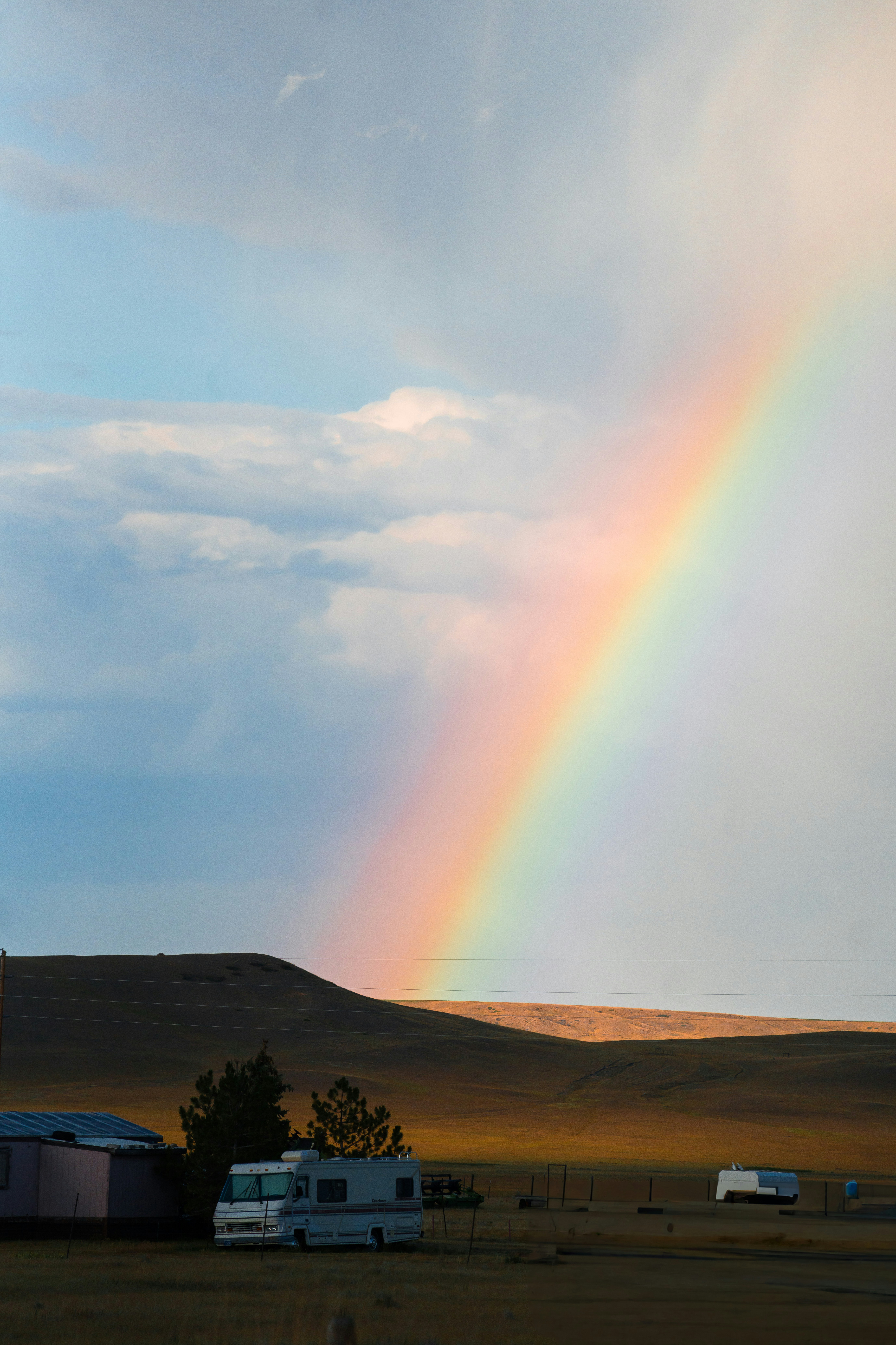 Chasing Rainbow, Quite Literally! | A vibrant rainbow arches over a rural landscape with rvs.