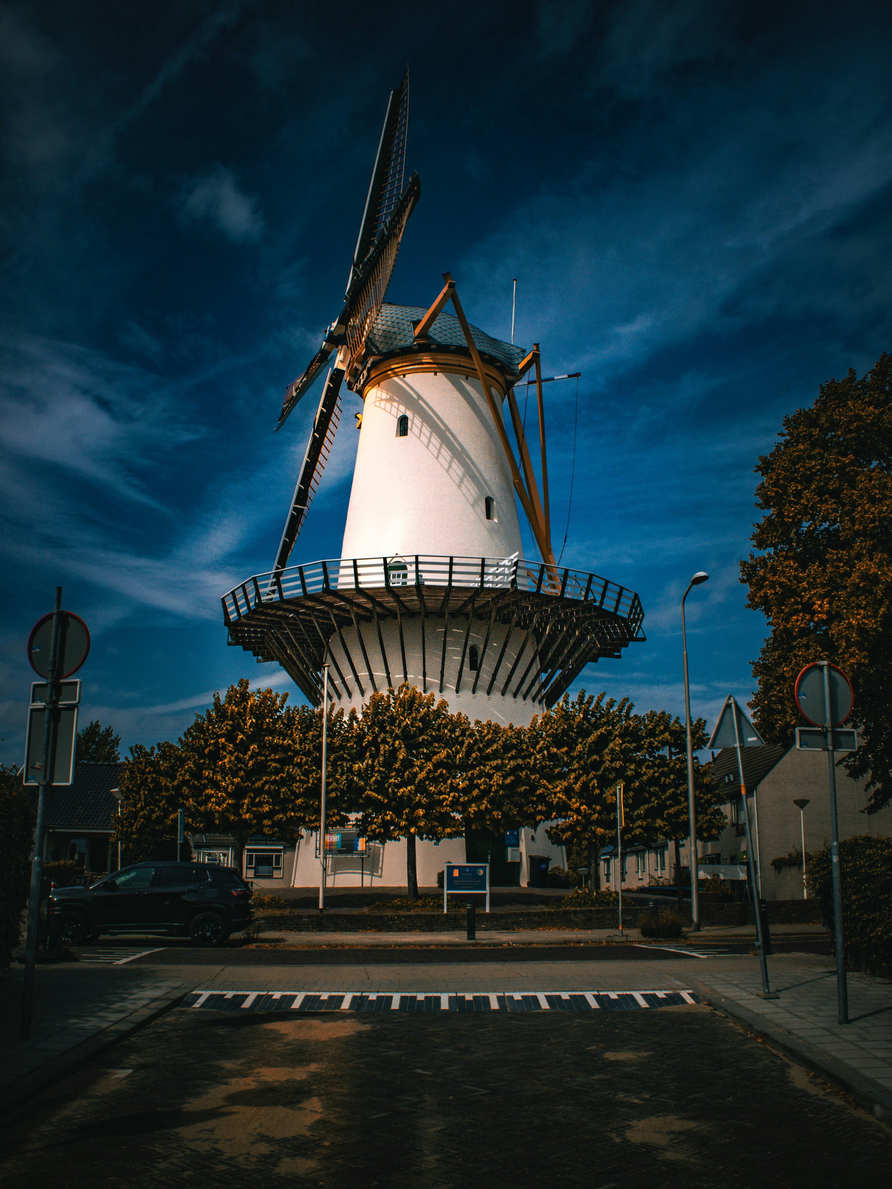 Molen de hoop | White windmill with large blades against a dark sky