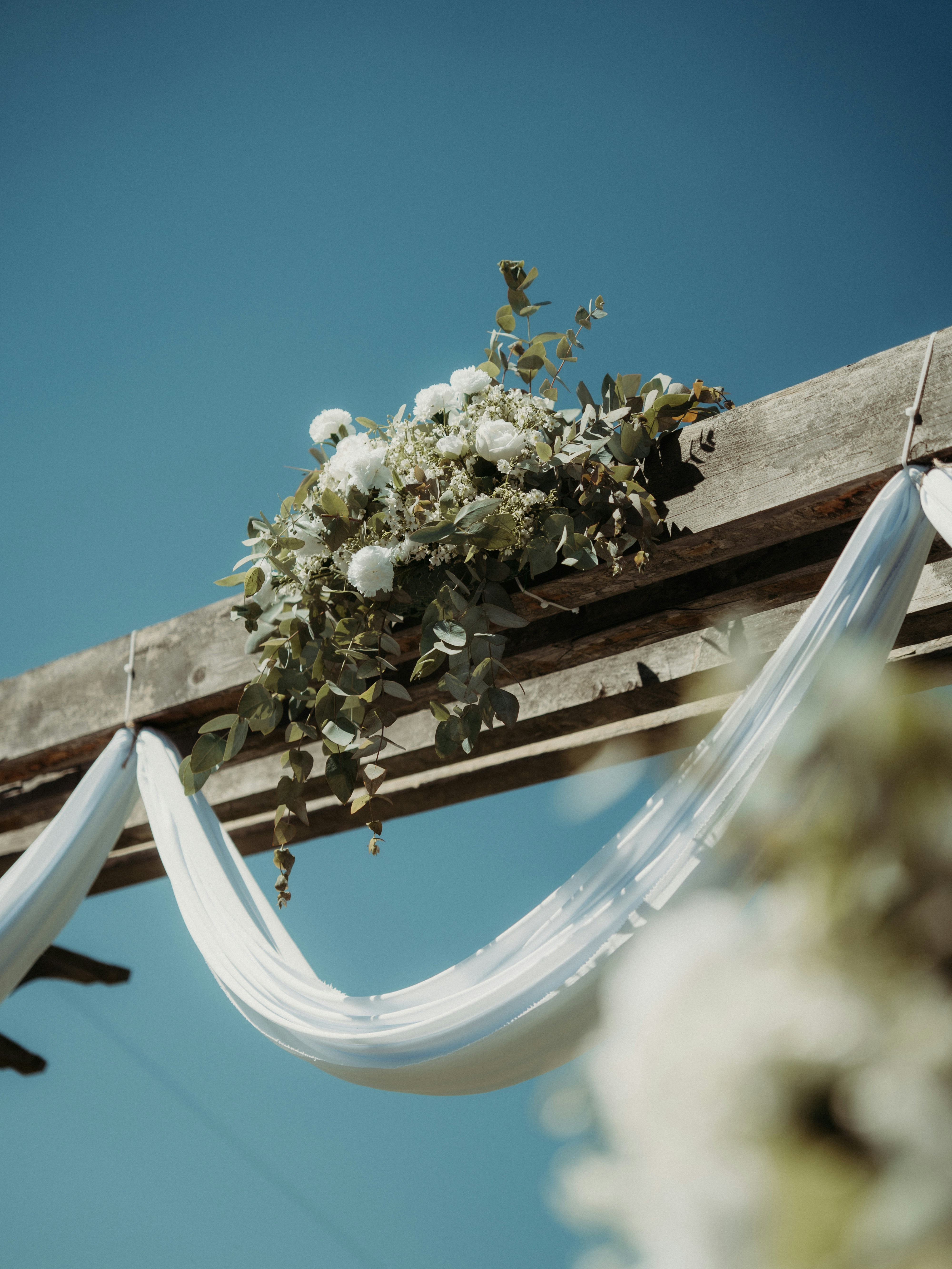 Wedding arbor with white flowers and flowing fabric.