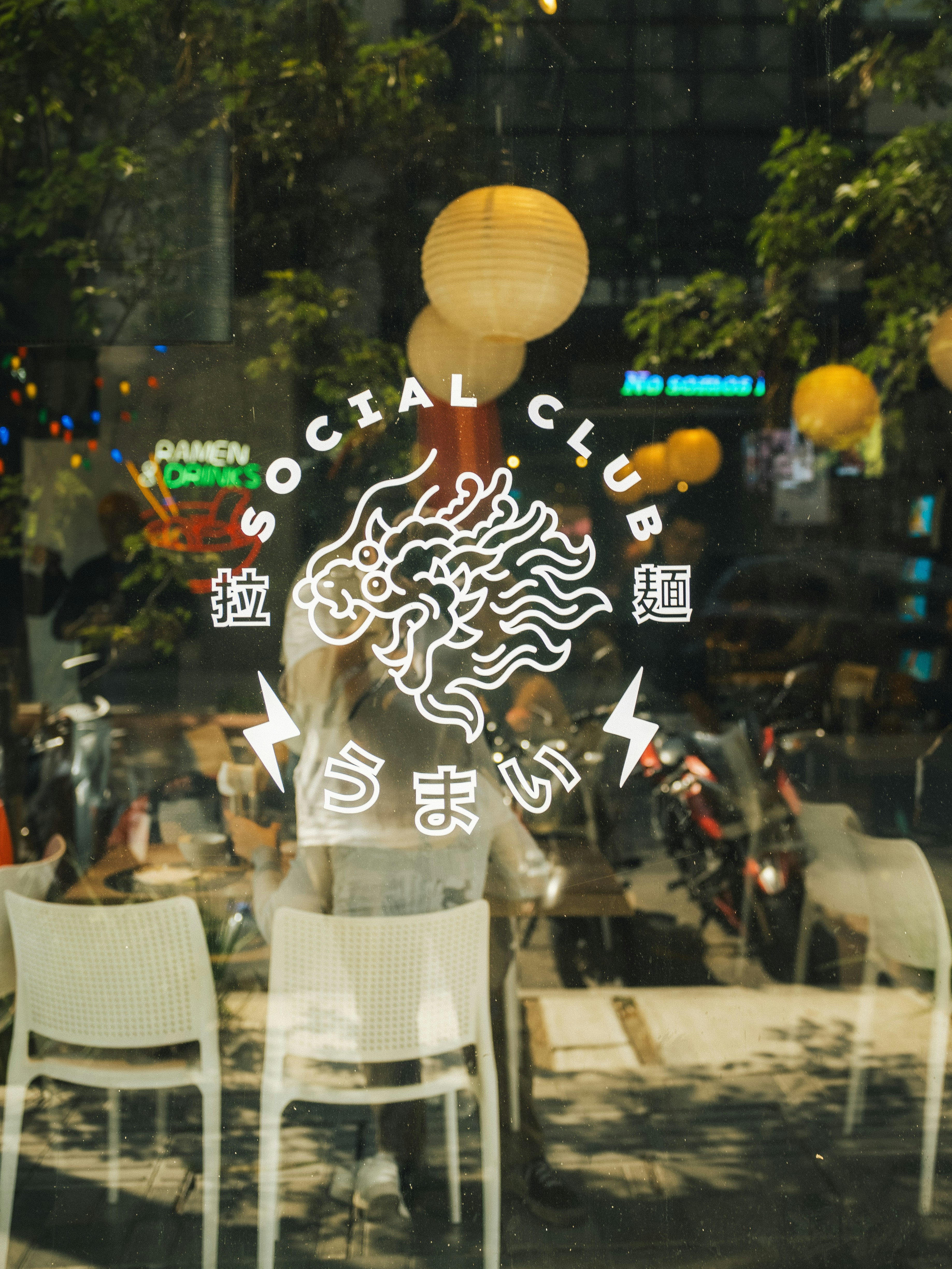 Restaurant window with "social club" logo and japanese text.