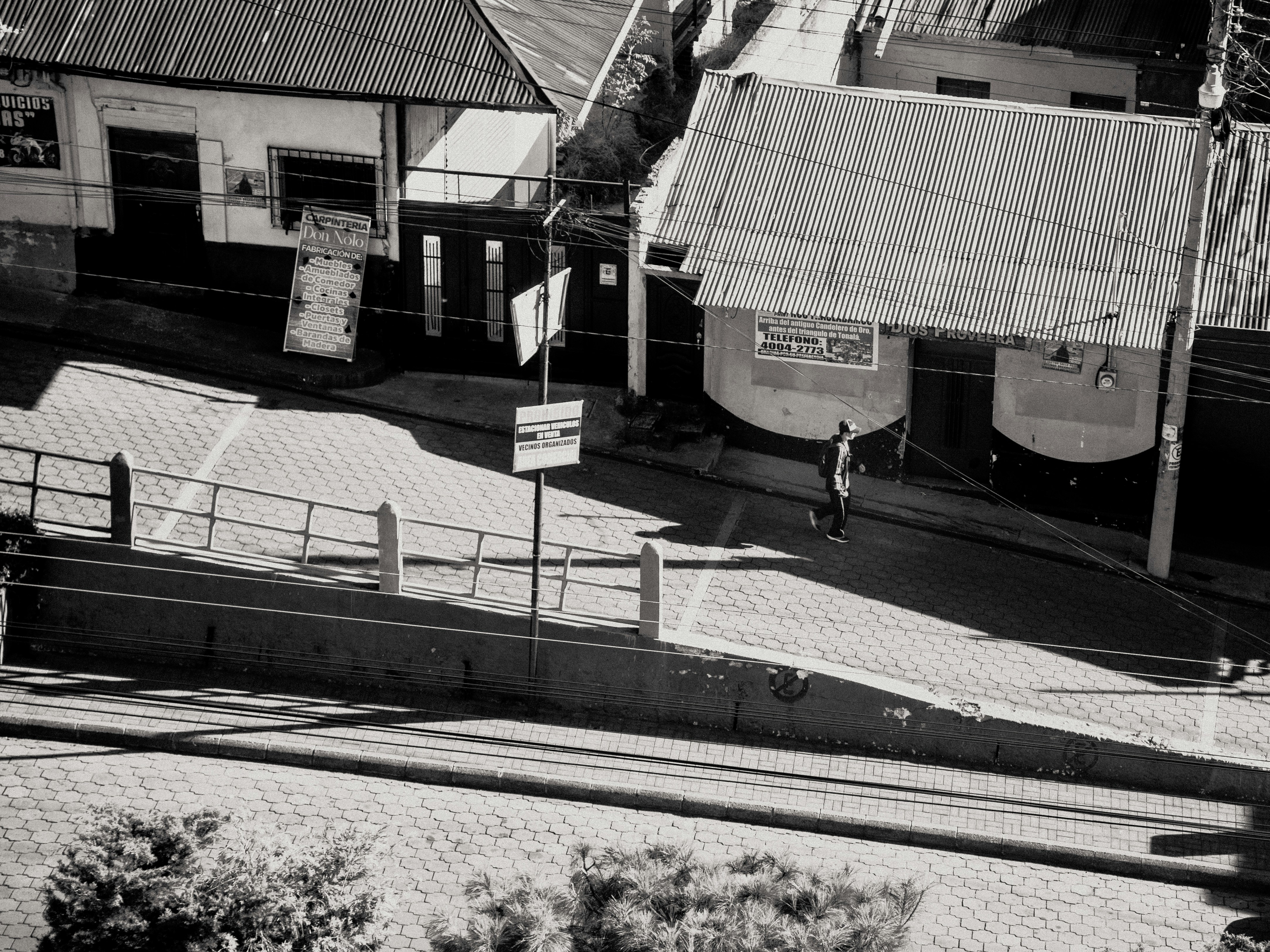 A person walks down a steep, cobblestone street.