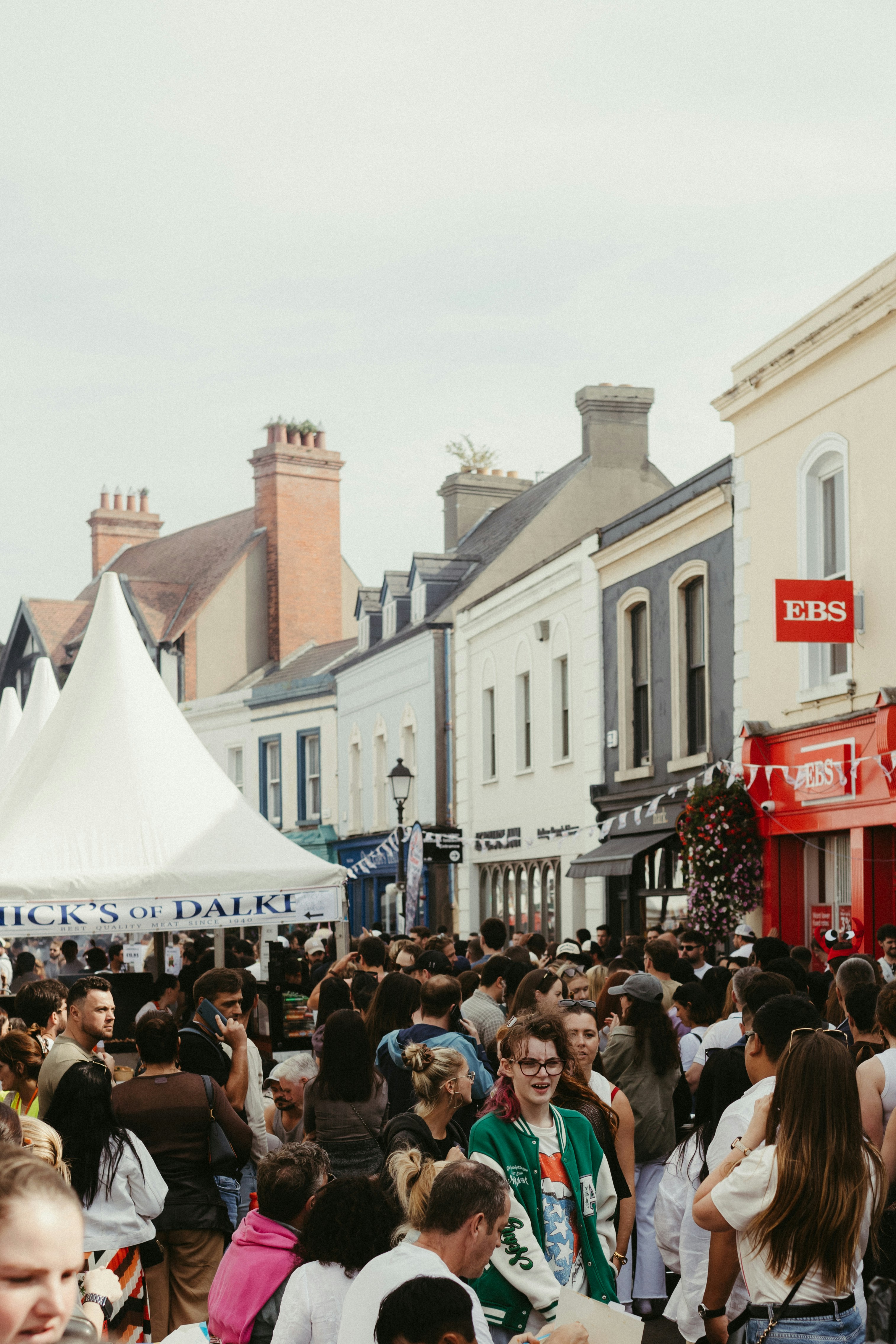 Crowded street festival with tents and buildings