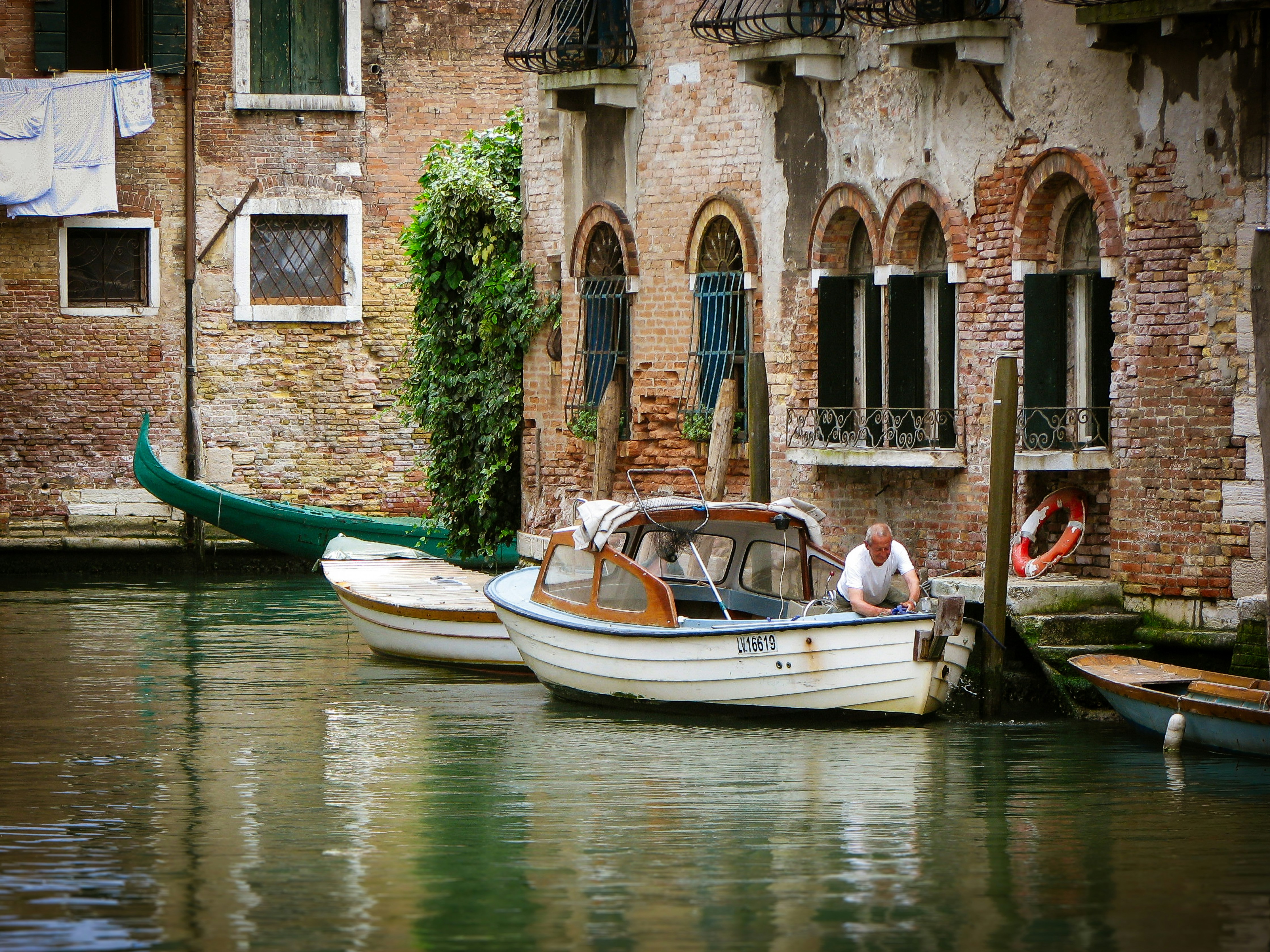 Shot in Venice, Italy. | Man working on a boat by a canal in venice