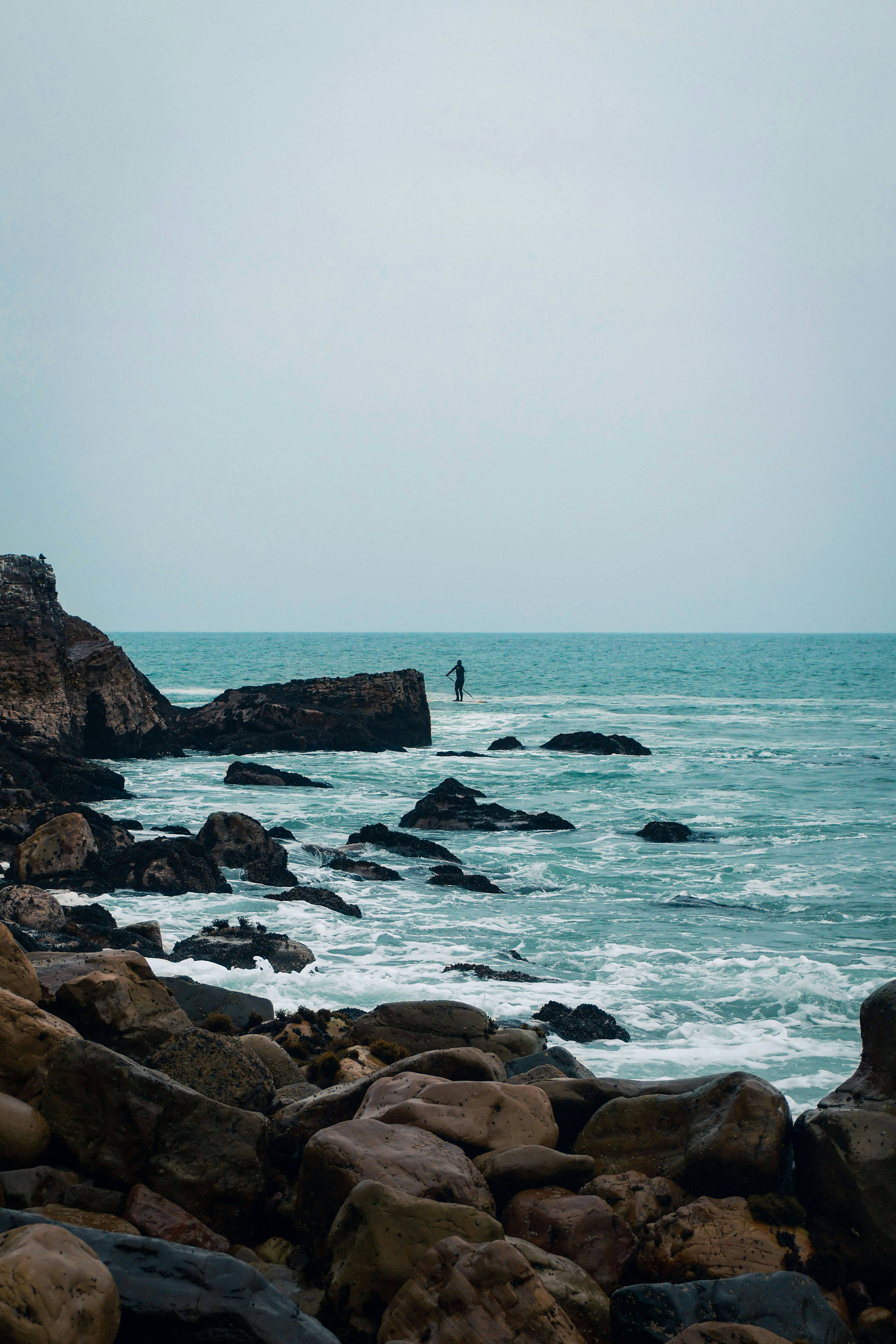 Person standing on rocks by the ocean