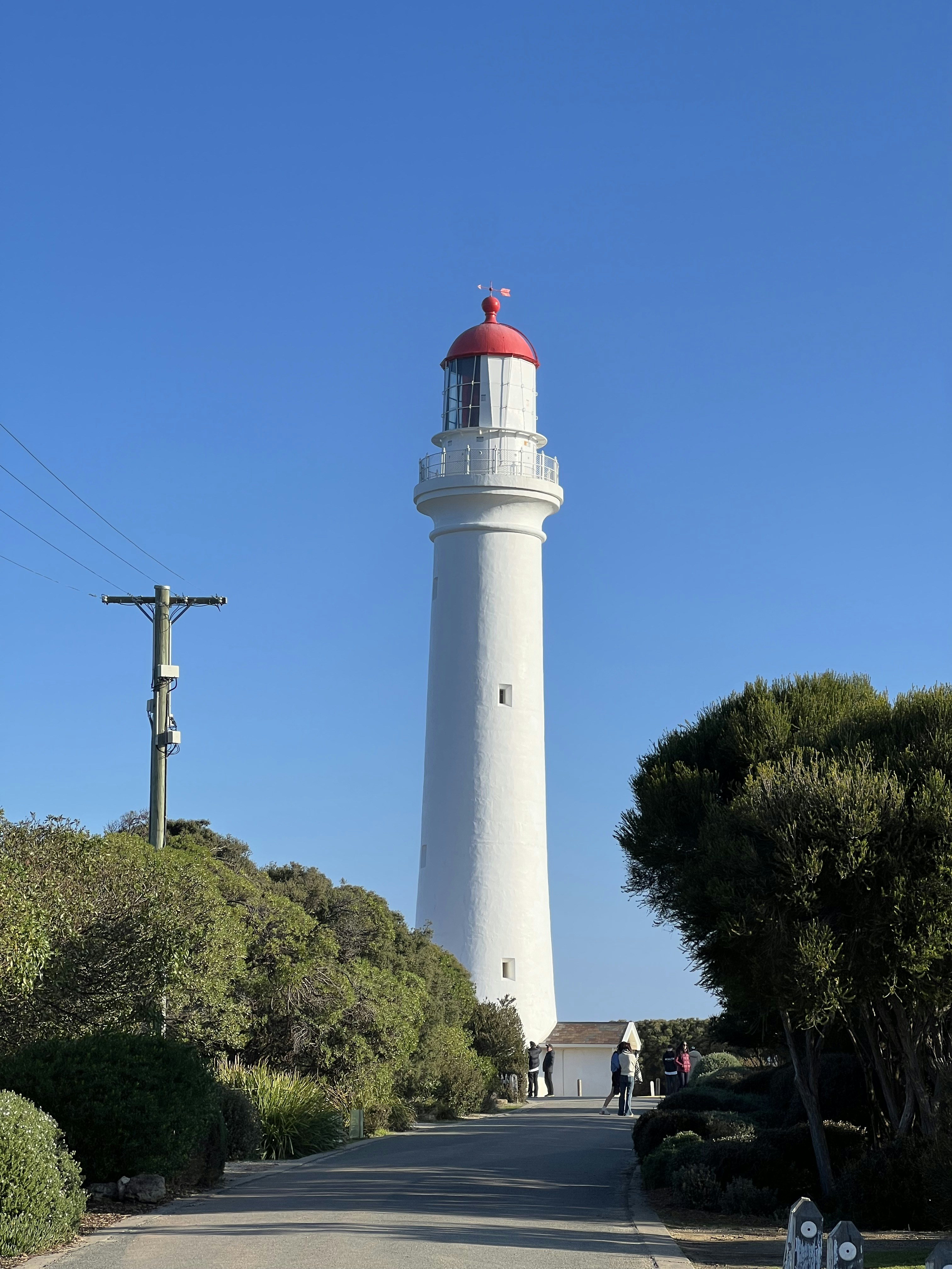 Tall white lighthouse with red top on a sunny day