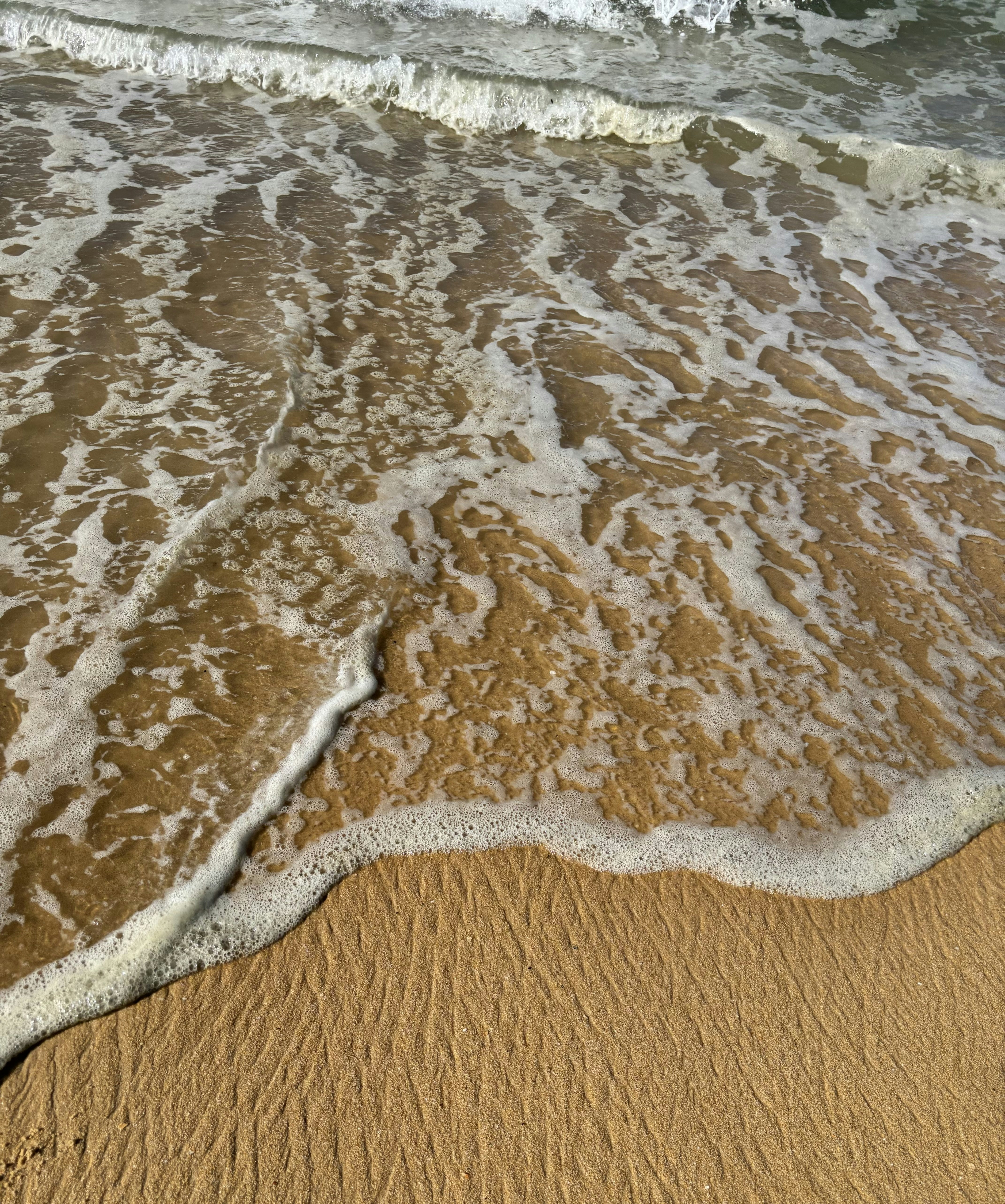Gentle ocean waves washing over sandy beach