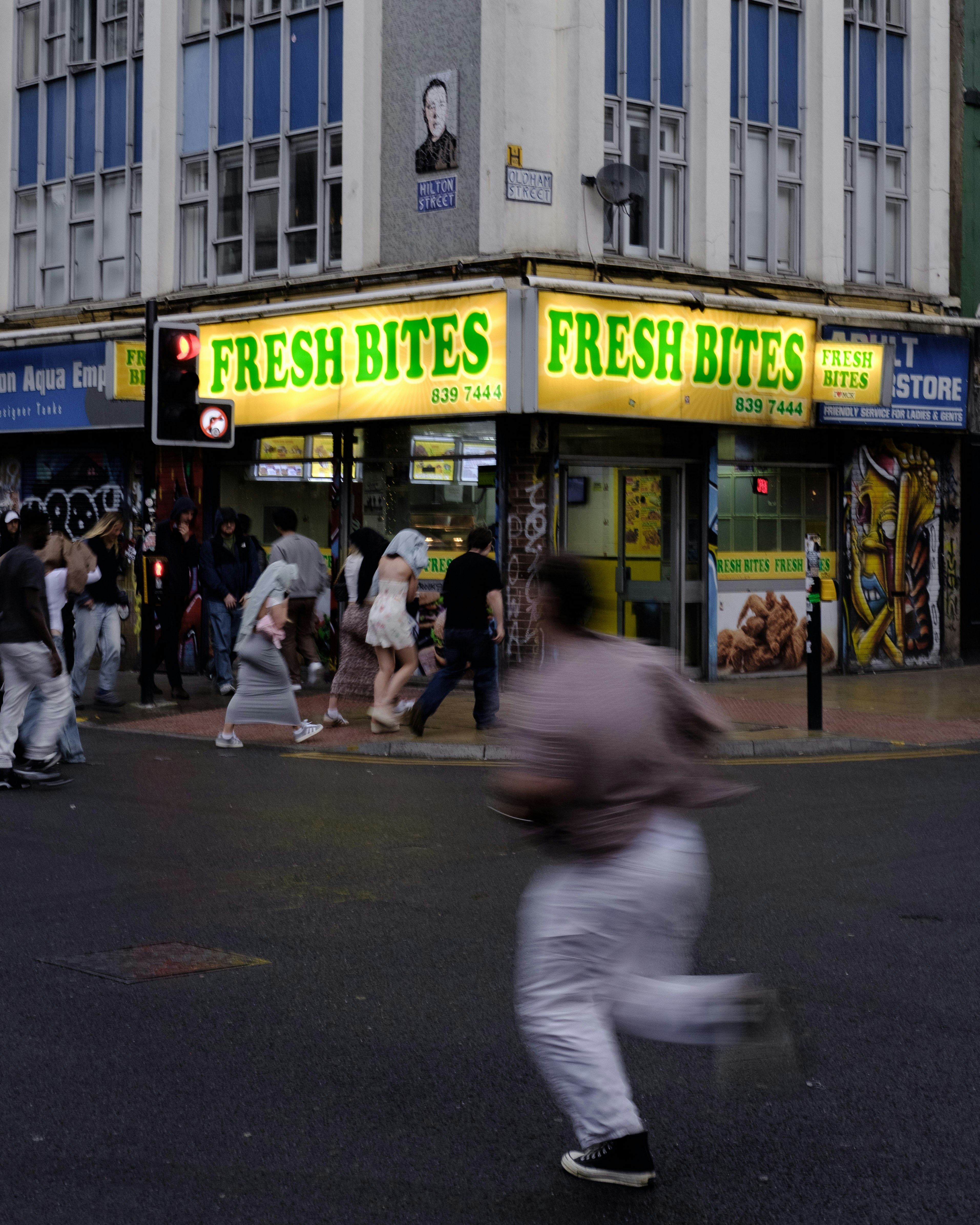 Fresh Bites fast food | People walk past a "fresh bites" store at dusk.