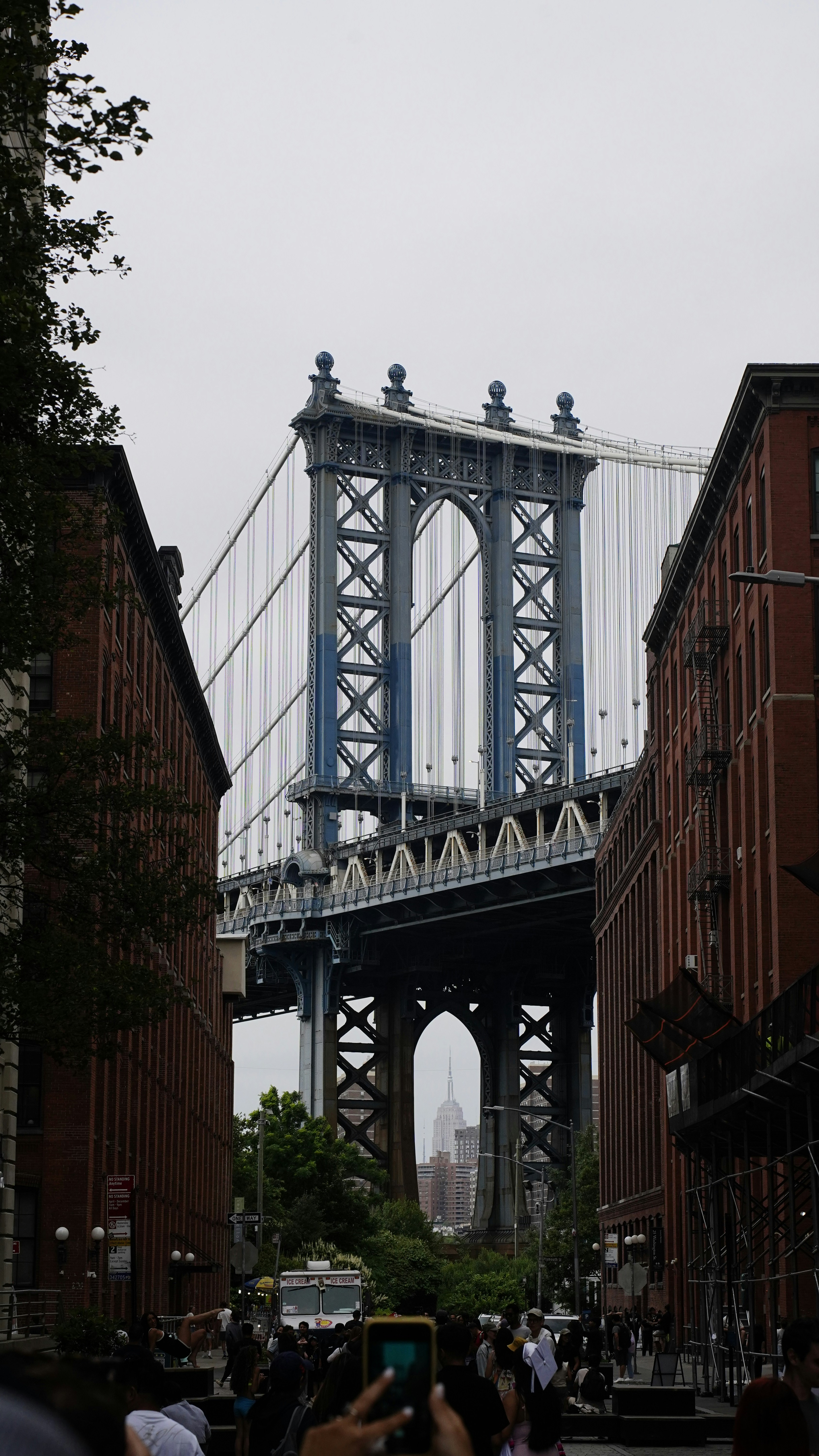 Manhattan bridge view between buildings with empire state building.