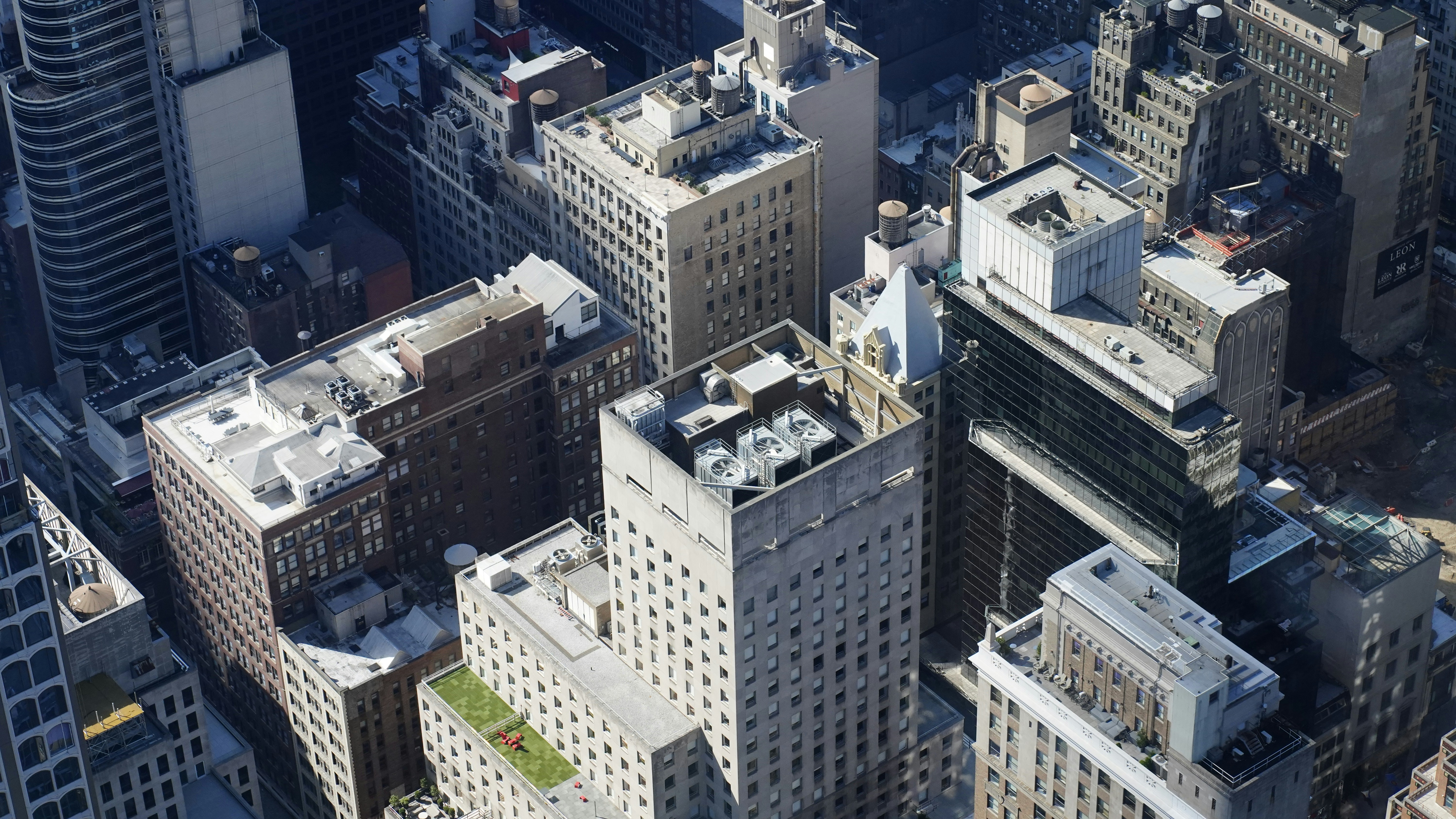 Aerial view showcasing a diverse array of urban rooftops, highlighting architectural variety and the interplay of light and shadow across the cityscape.