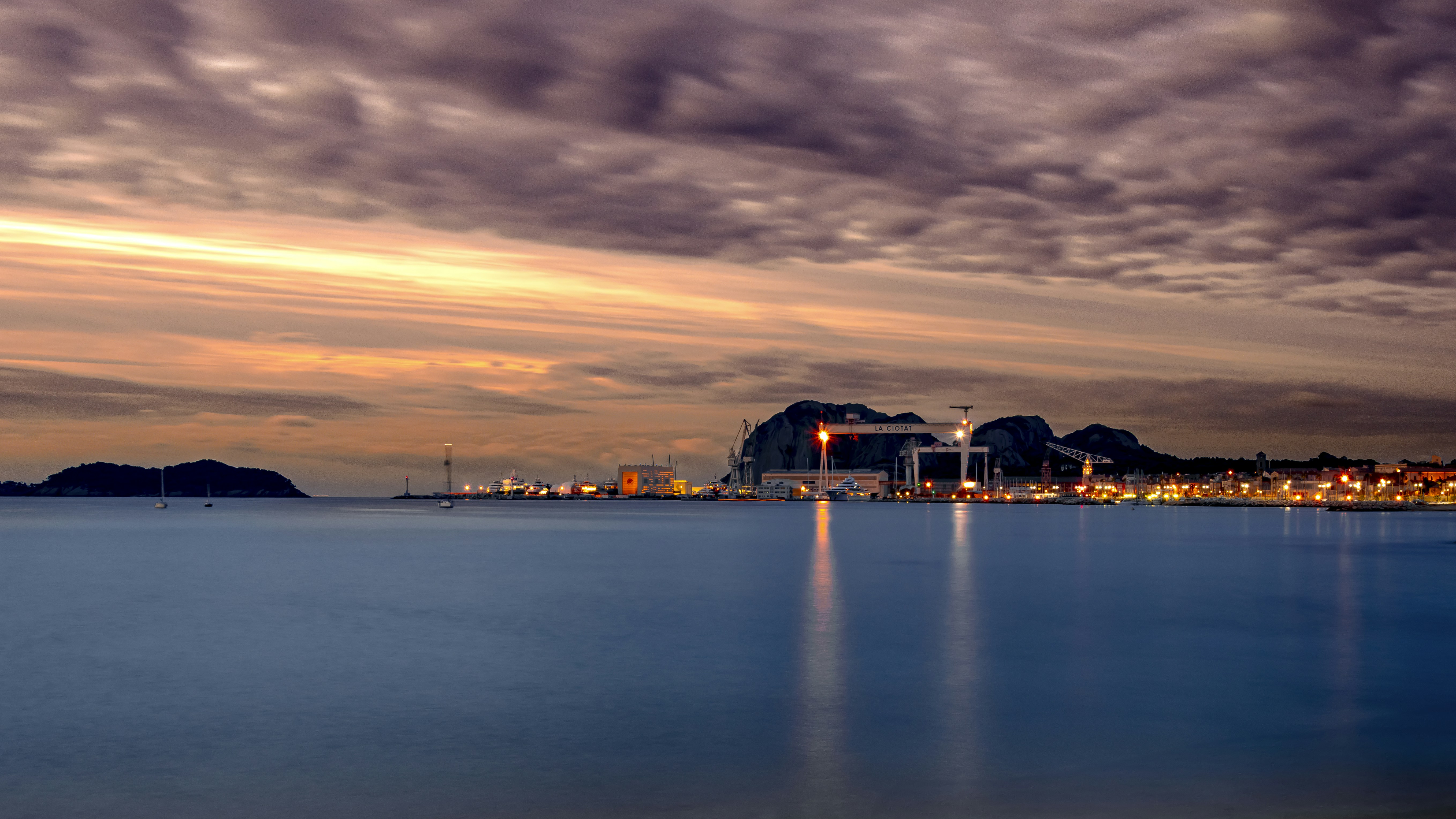 Coastal town illuminated at dusk with dramatic clouds