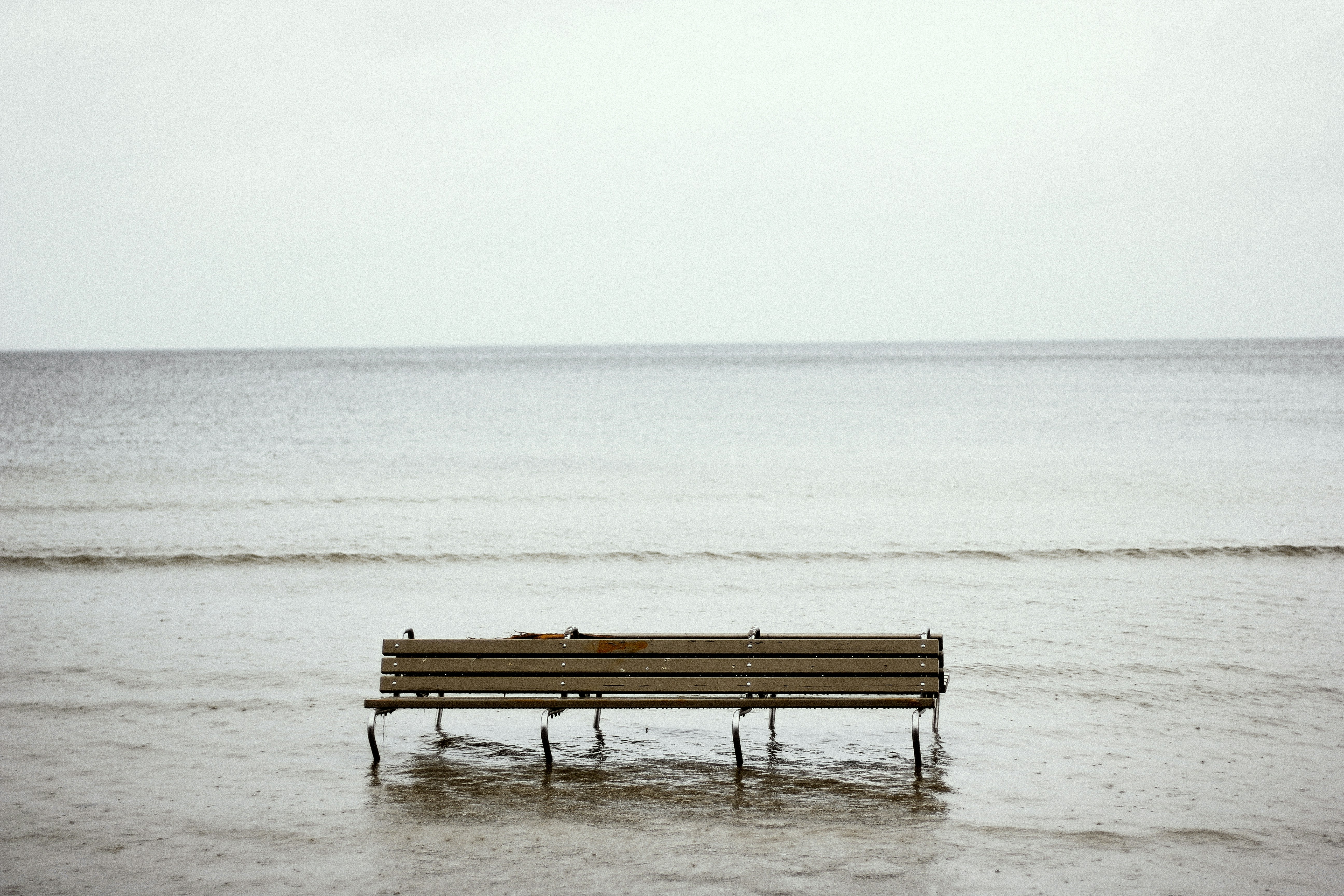 Bench sits in shallow water by the ocean